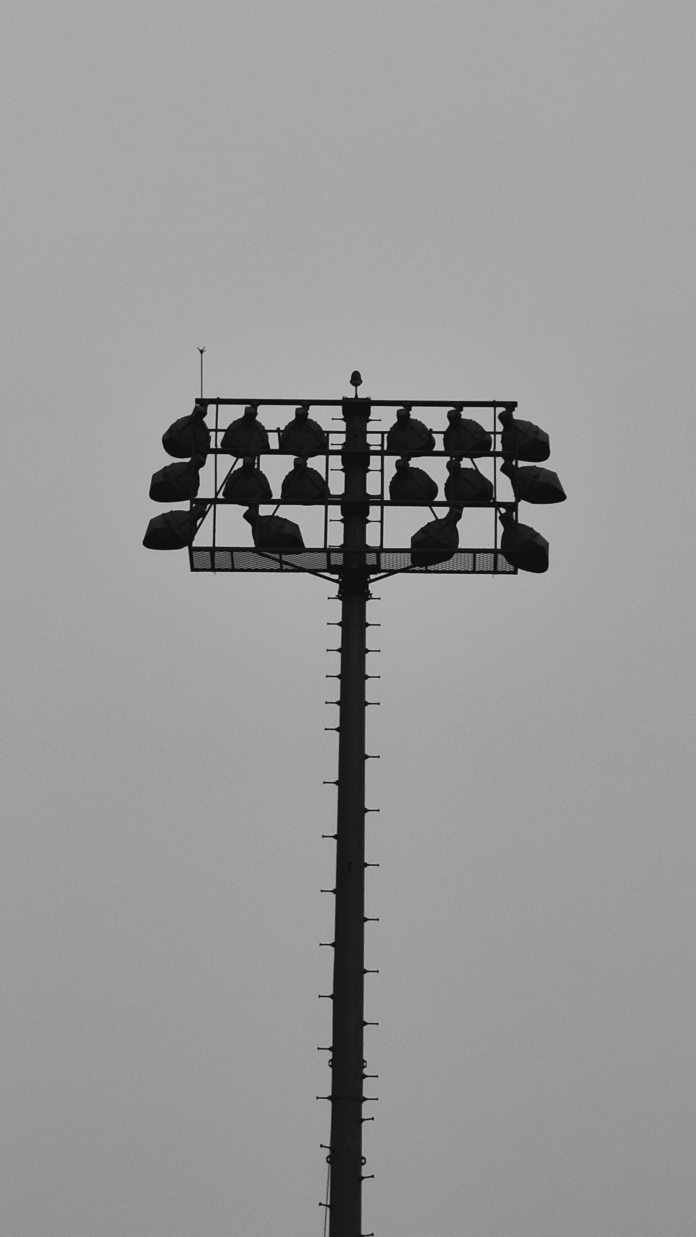 Silhouetted Floodlight Mast Against a Pale Sky
