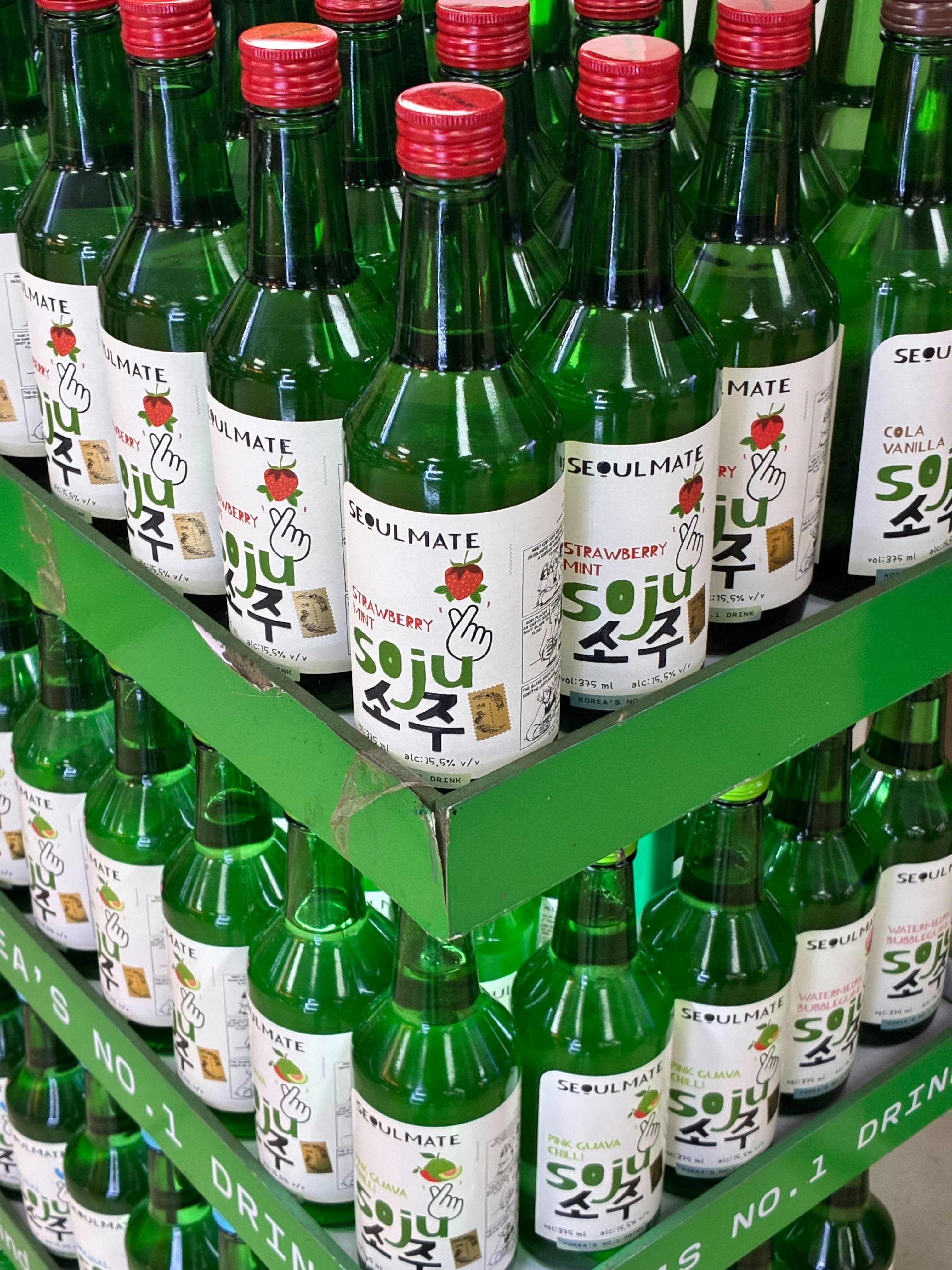 Row of Green Soju Bottles with Red Caps in a Market Shelf