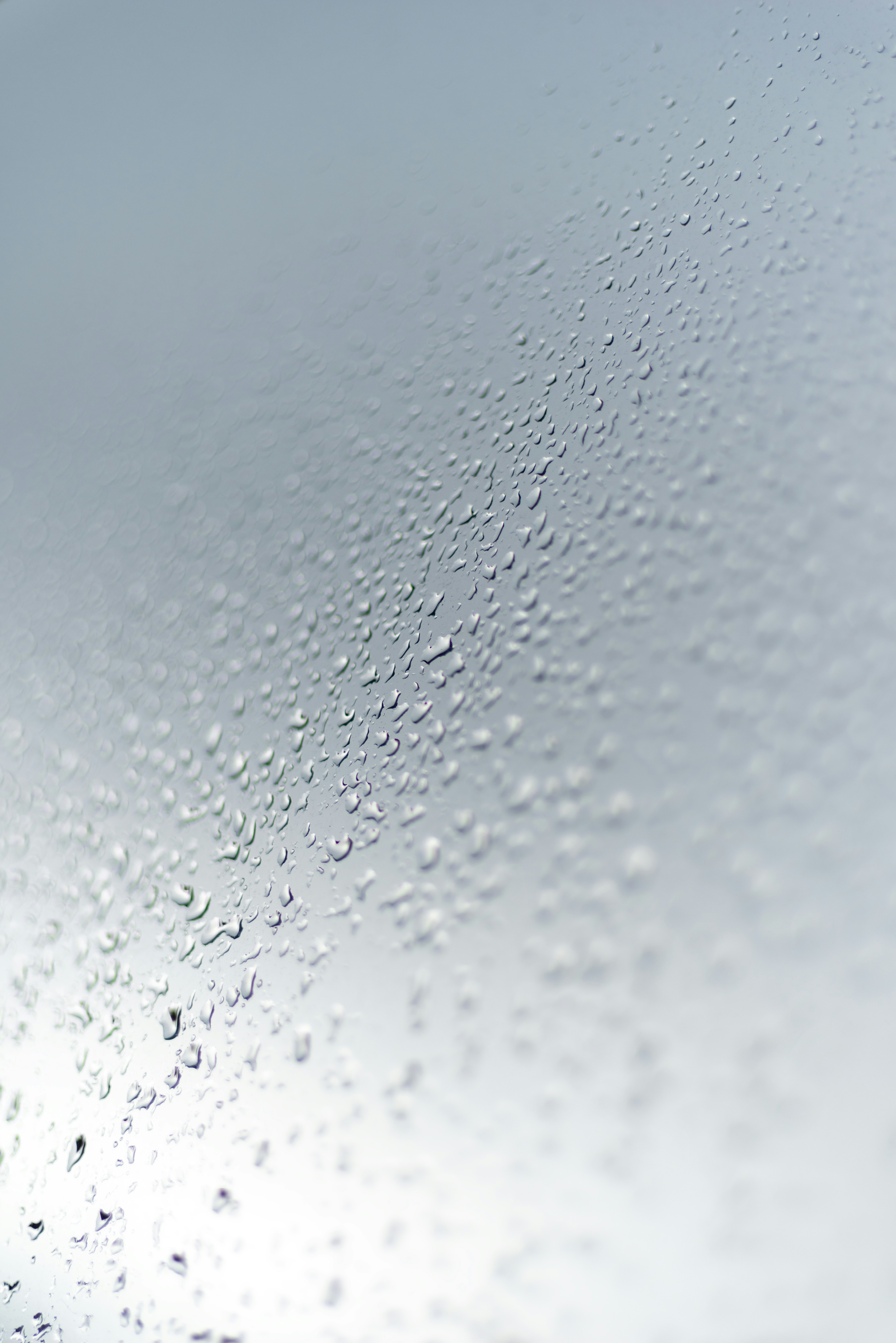 Raindrops on a window pane with a blurred background.