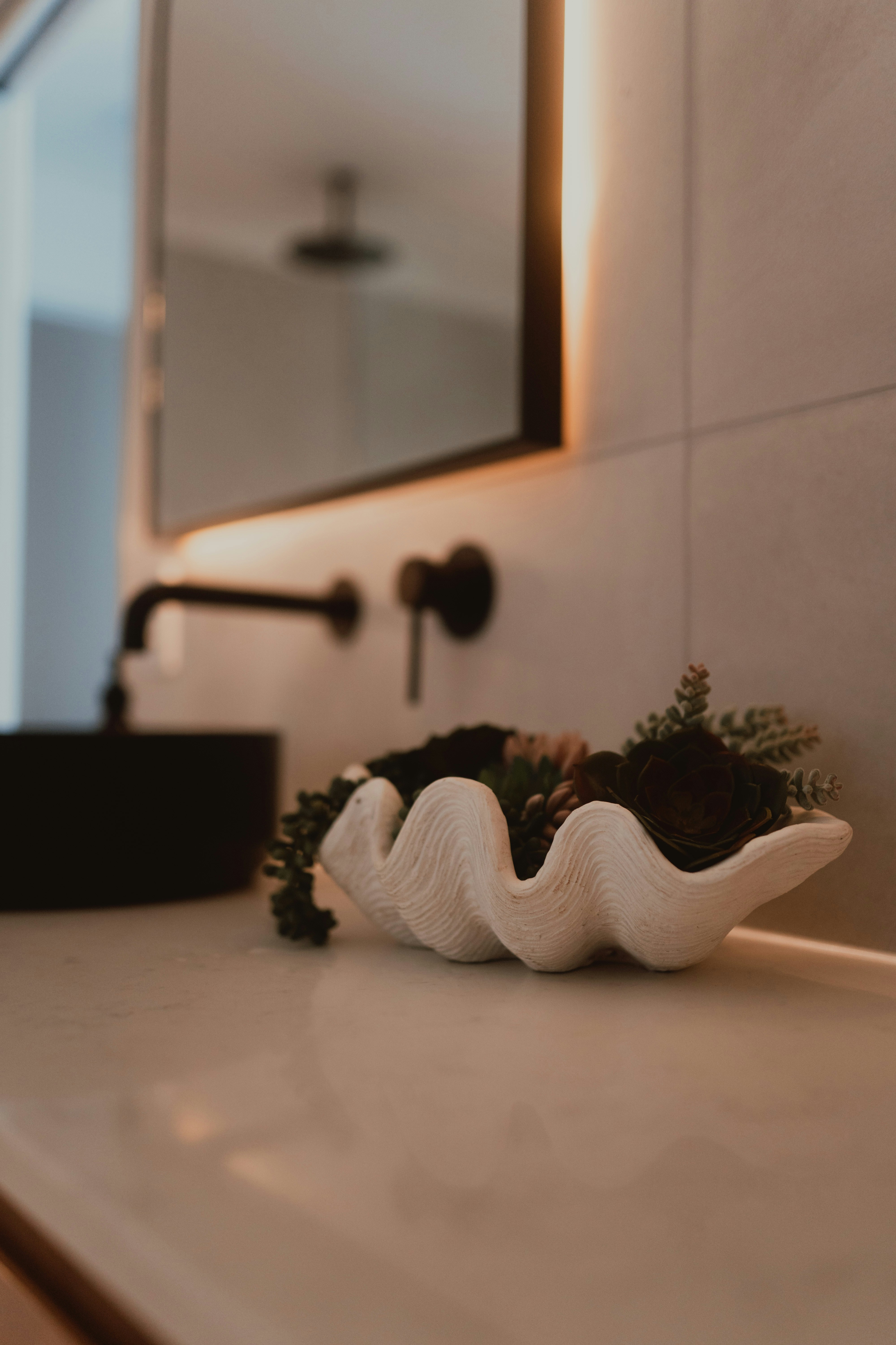 Shimmering Shell Vase on a Marble Vanity by a Backlit Mirror