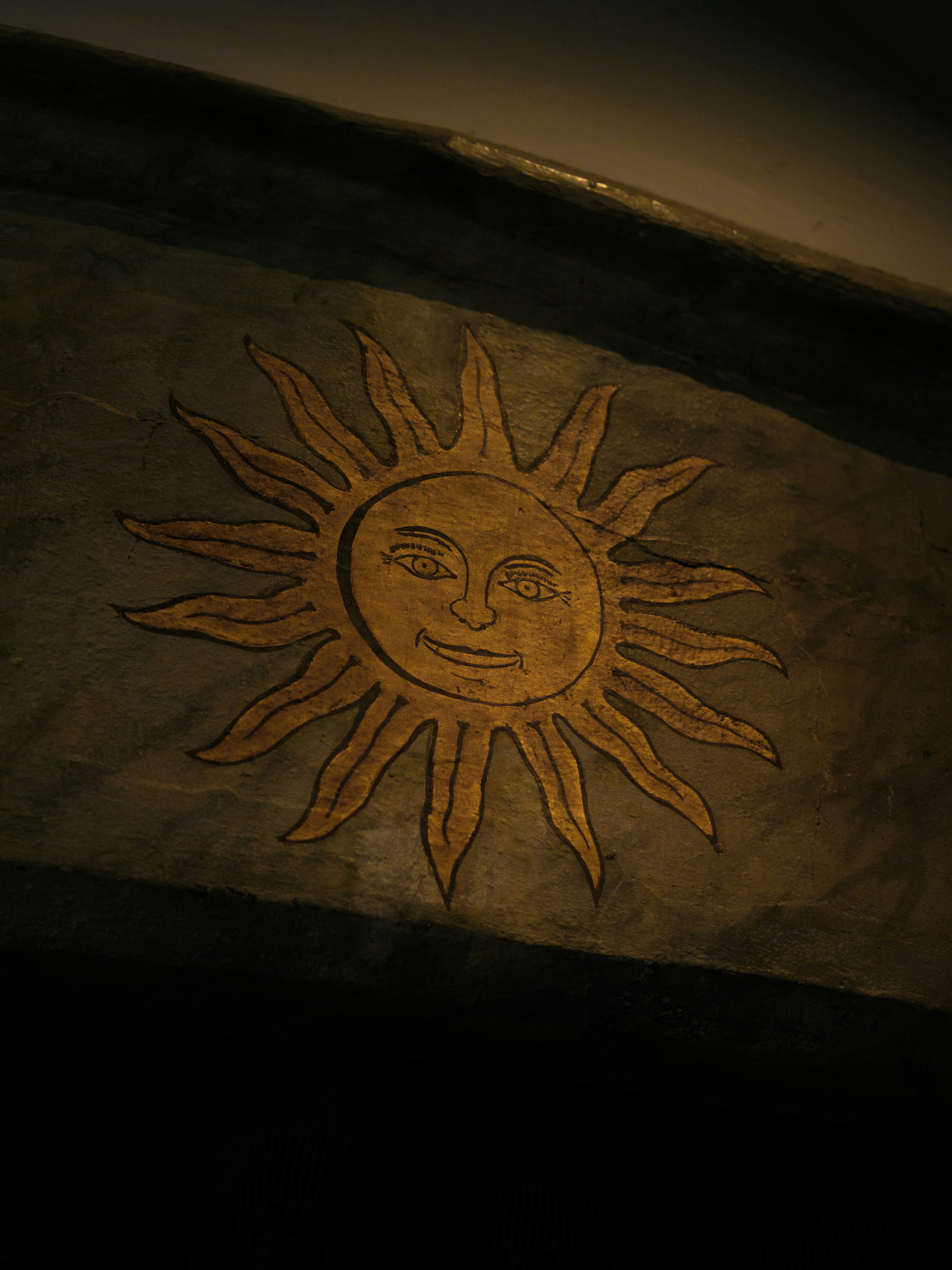 Sun carved in stone: a warm, ancient gaze under dim ambience