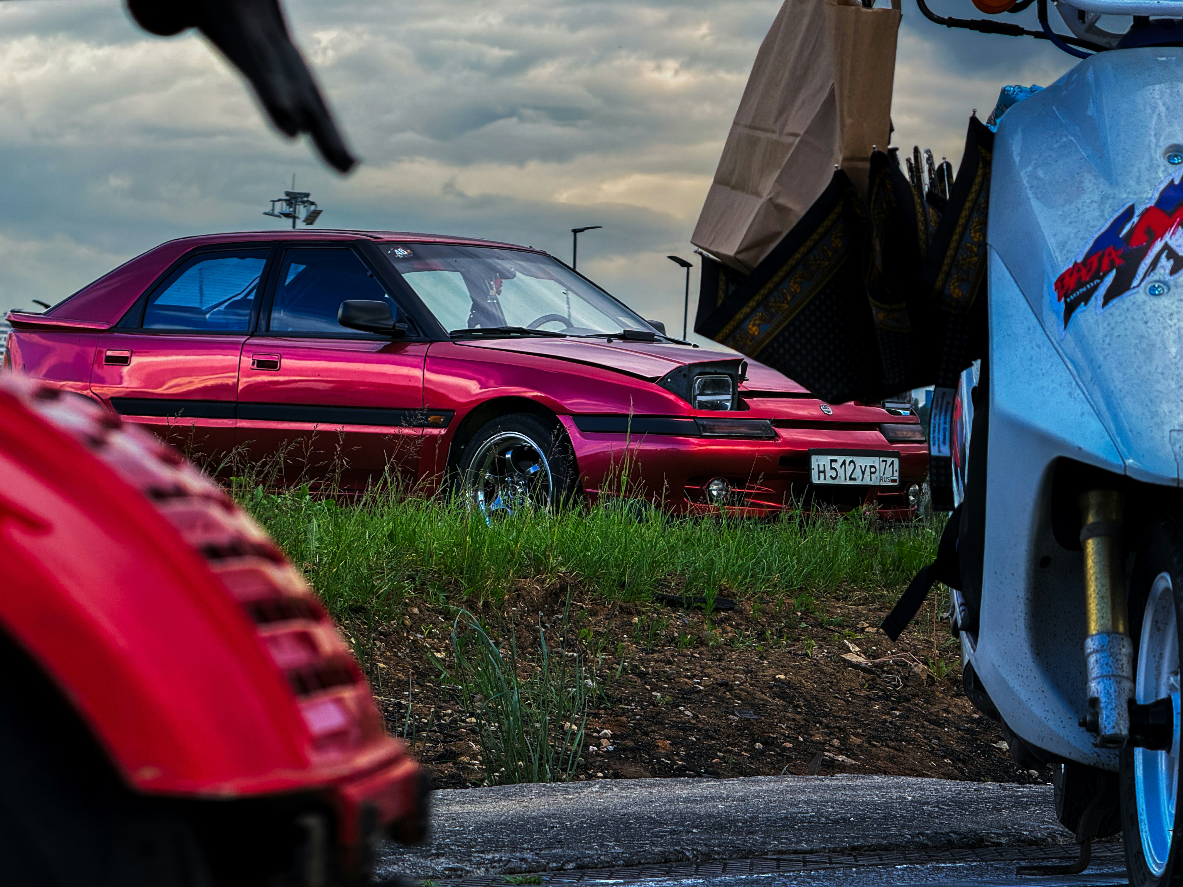 Crimson Classic: A Vintage Sedan Framed by Industrial Scraps