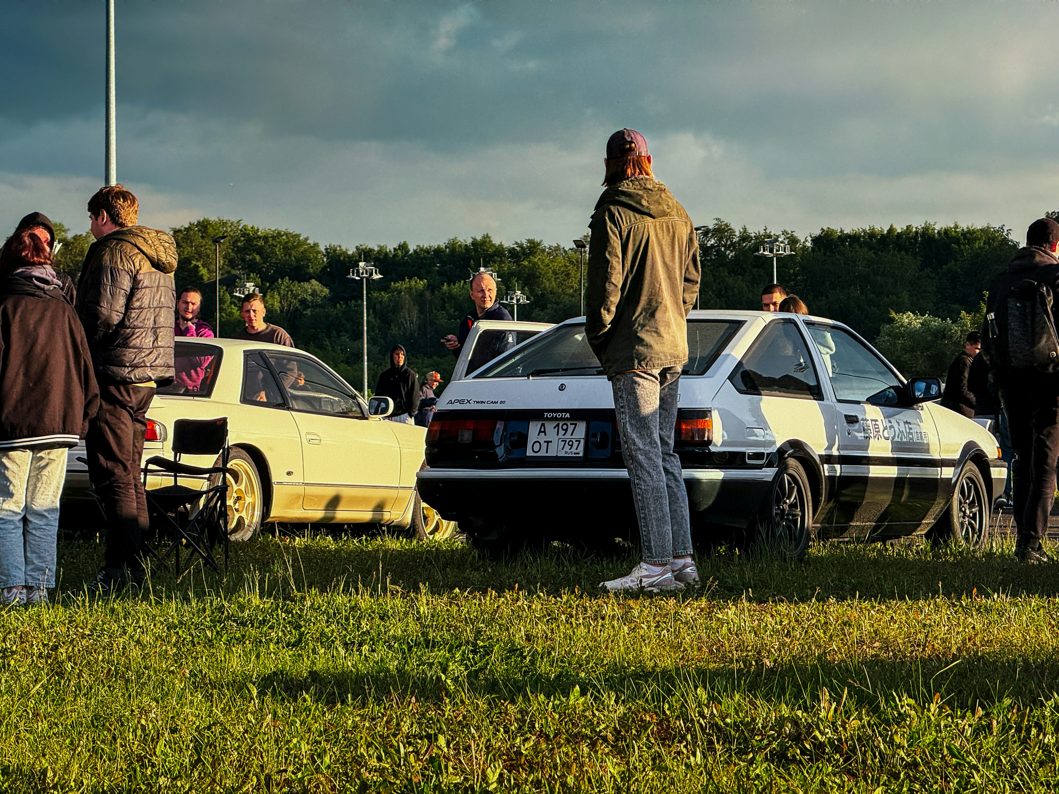 Crowd around vintage race cars on a sunlit field