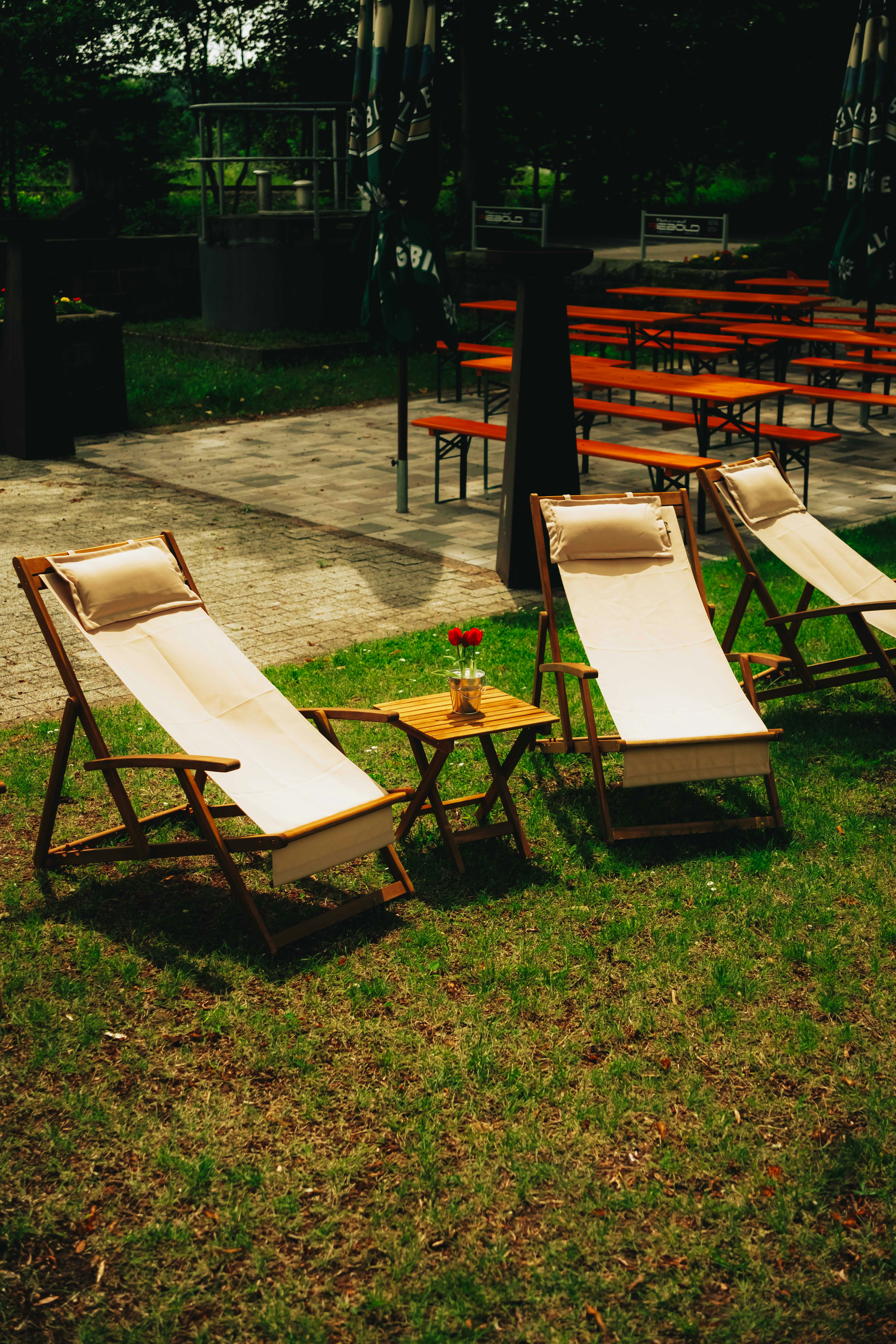 Sunlit lounge: two canvas sunbeds with a tiny flower table in a garden setting