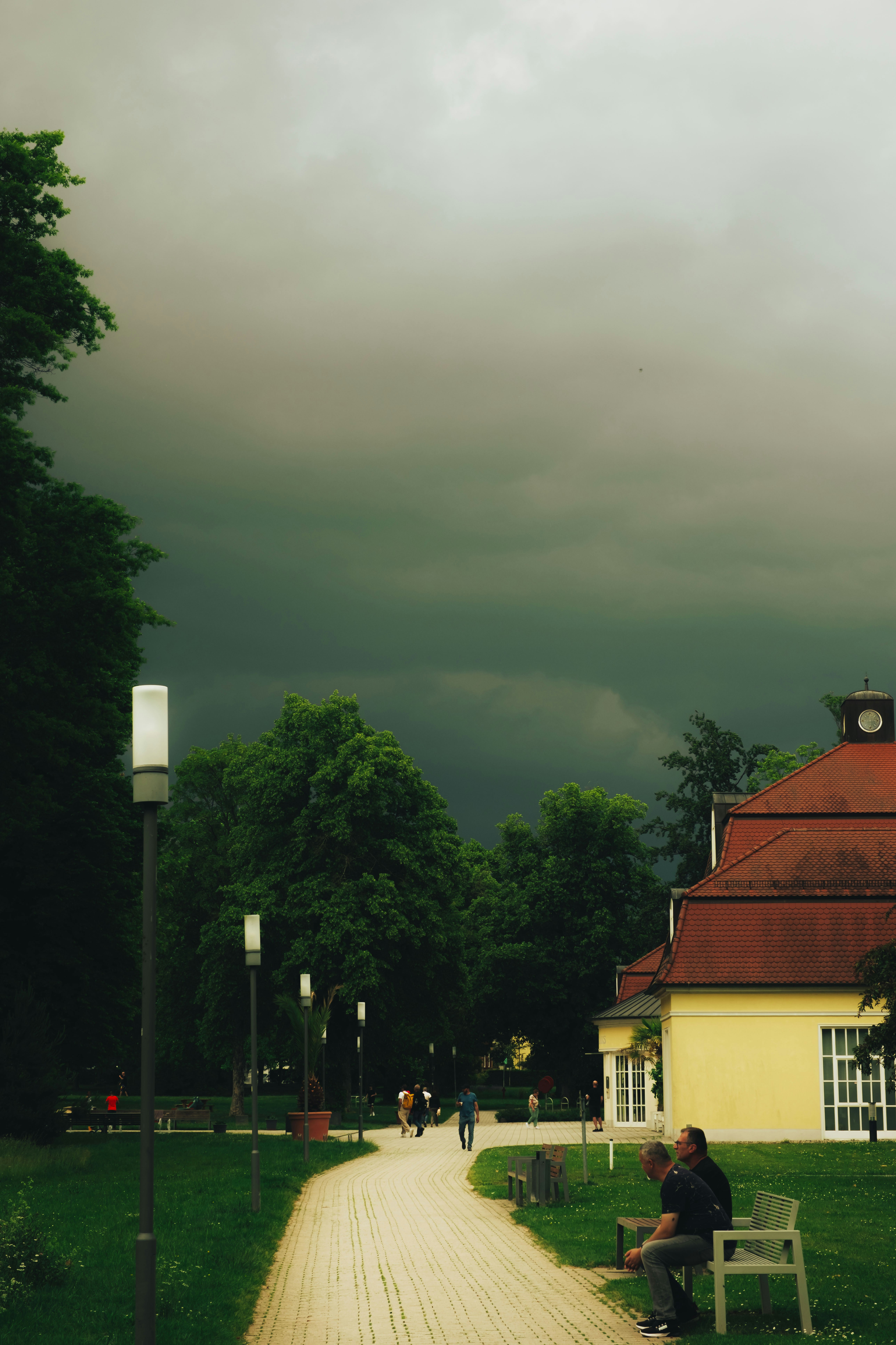 Stormy sky over a park path and a yellow building.