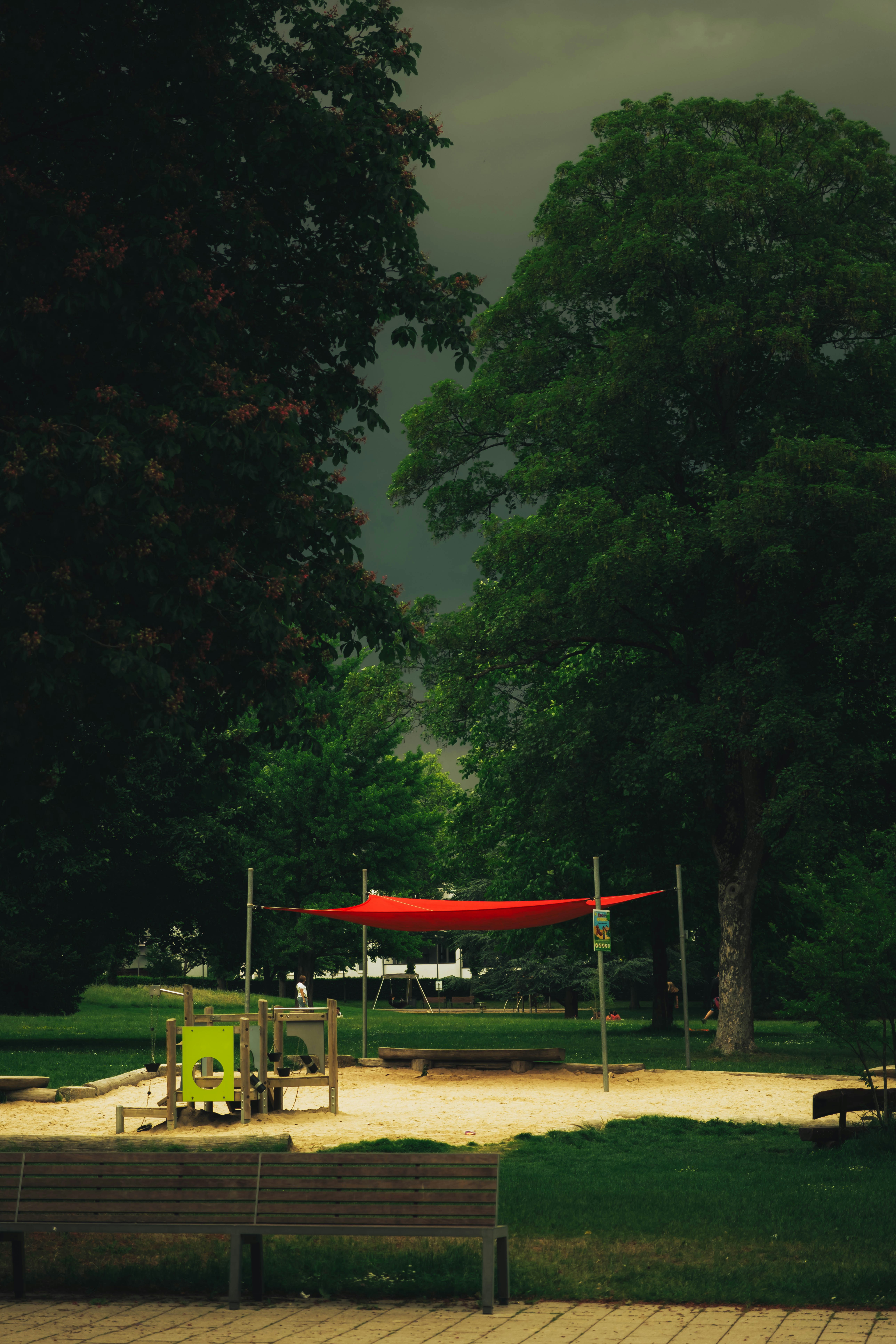 Red Canopy Overplay: A Quiet Playground Under Stormy Light