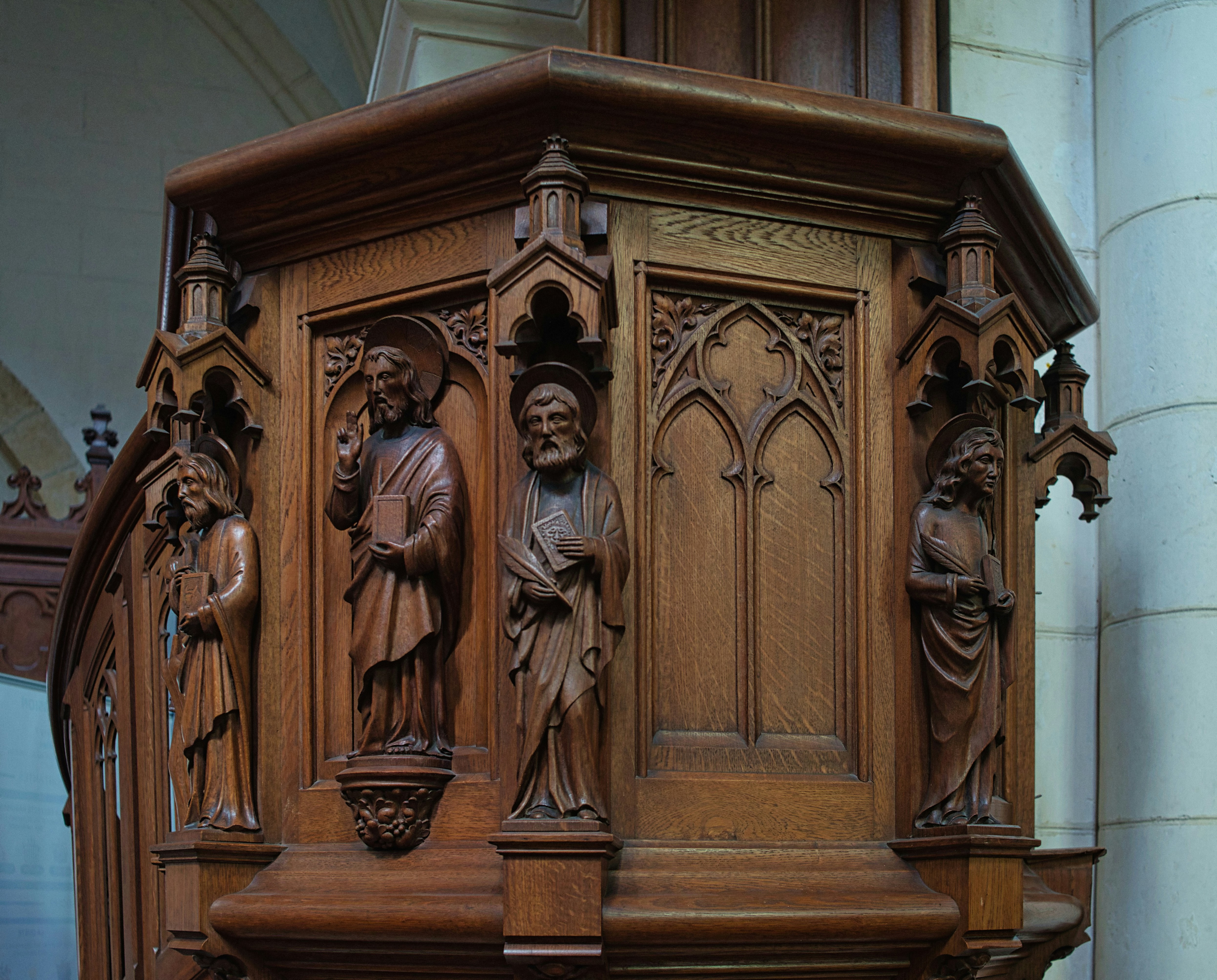 Carved saints on a church pulpit: timber figures guard a sacred niche