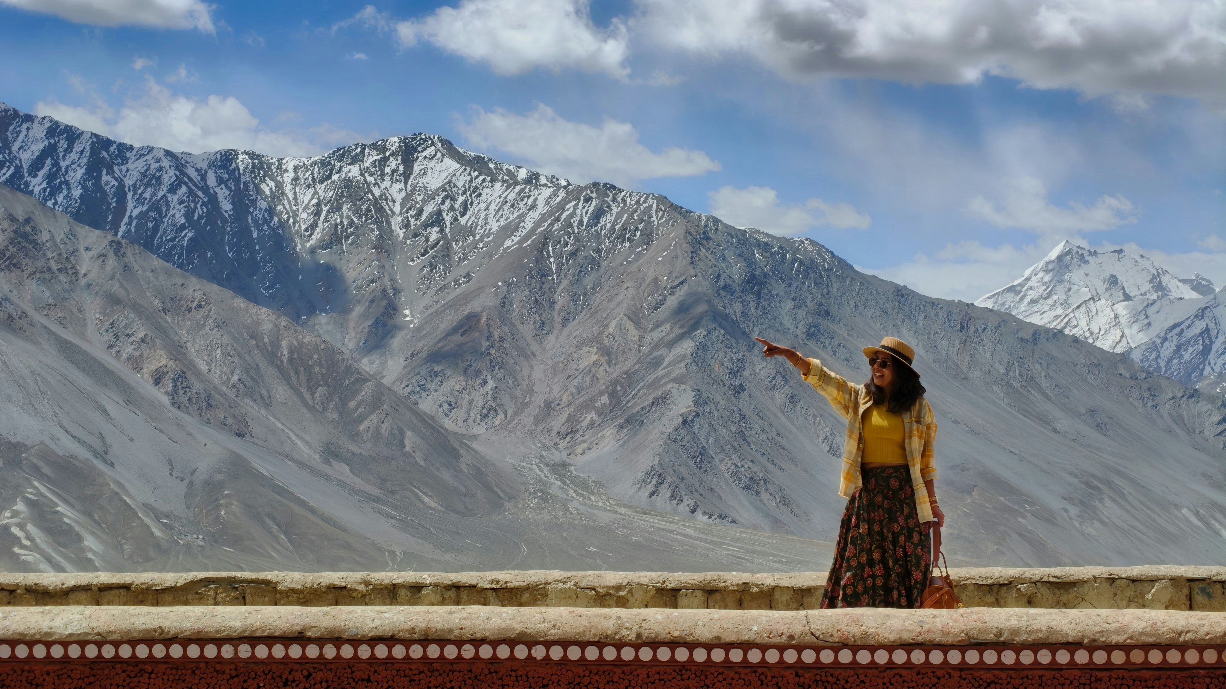 Ridge-Top Guide: A Distant Wanderer Points Toward Snow-Capped Peaks