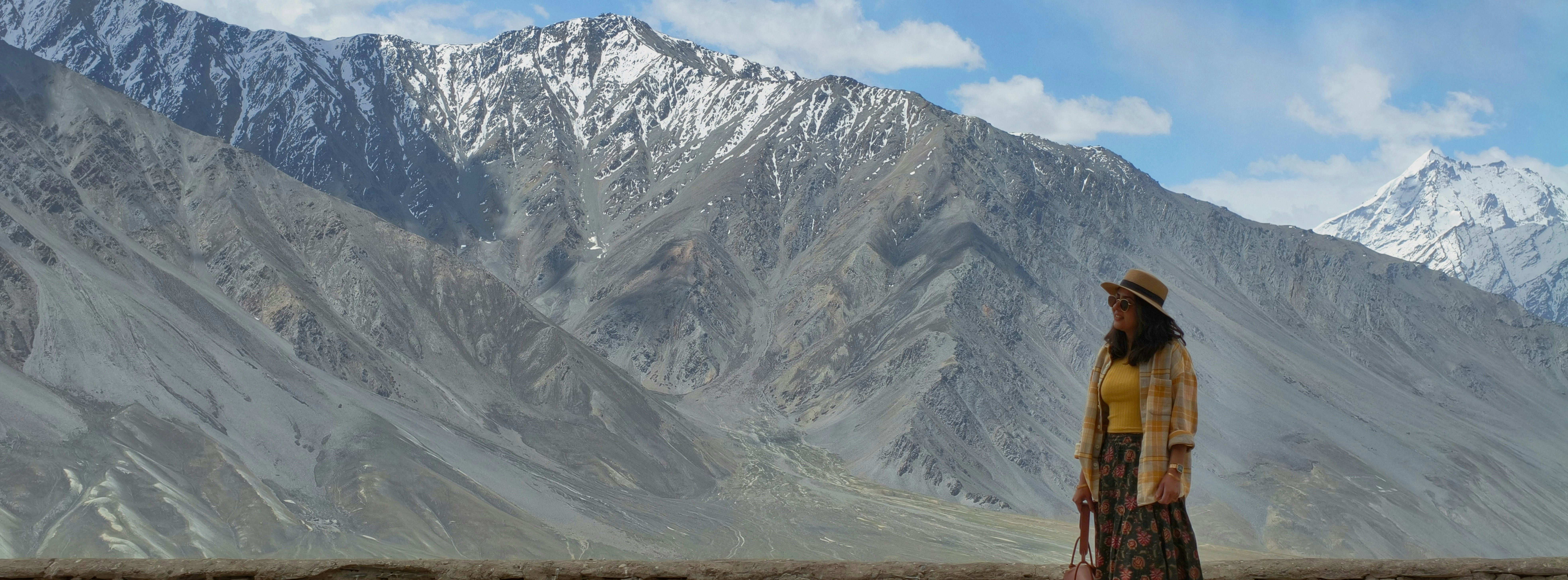 A person stands before majestic snow-capped mountains.