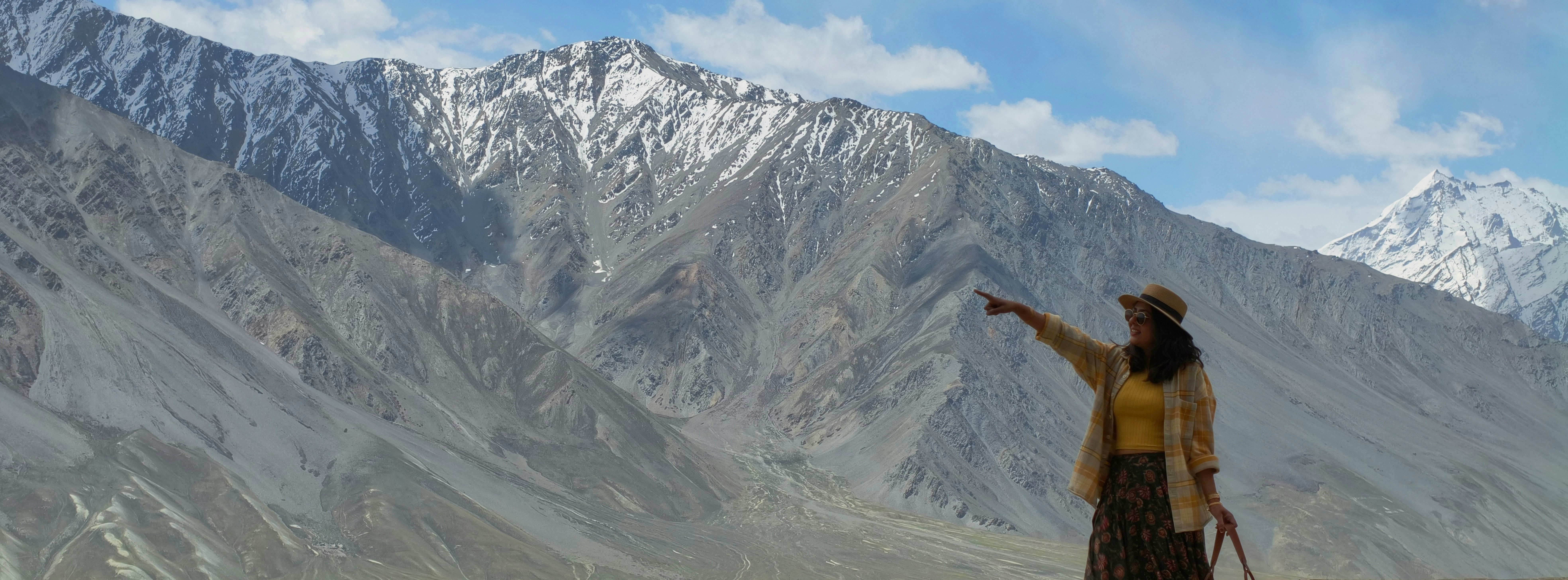 A woman points towards majestic snow-capped mountains.