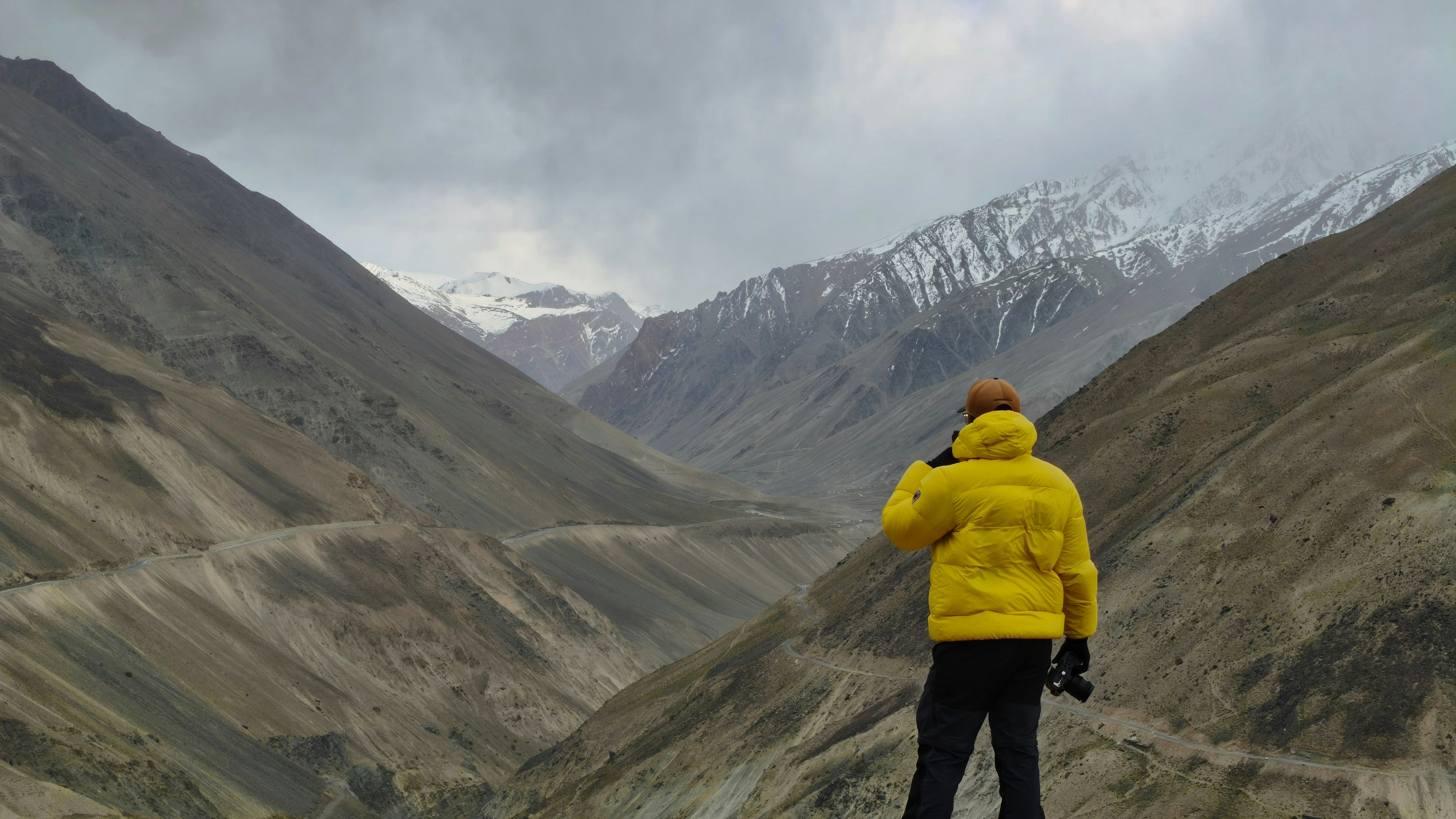 Bold Traveler in a Yellow Jacket Bridges Valleys of Snowy Peaks