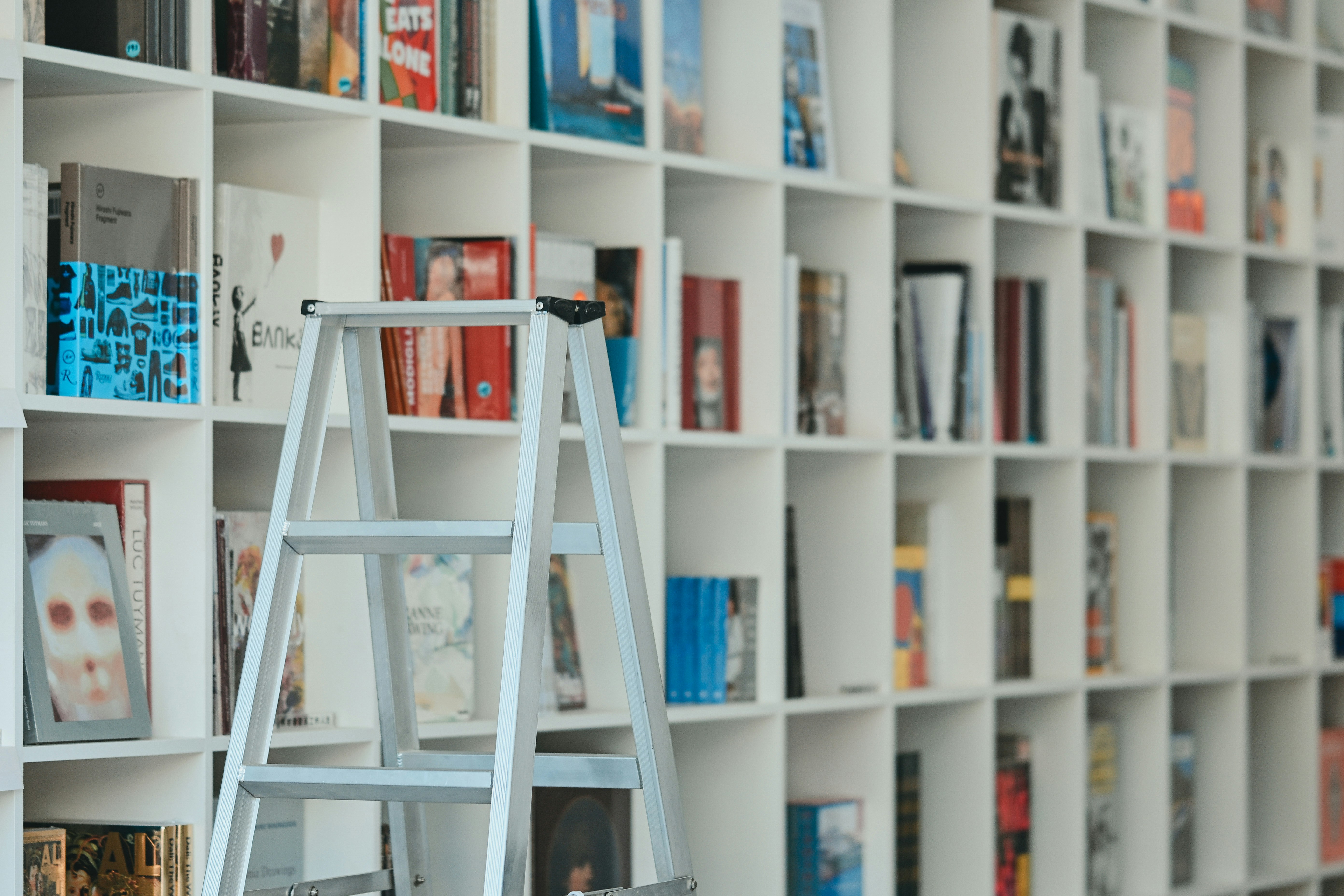 White stepladder against a bookshelf filled with books.