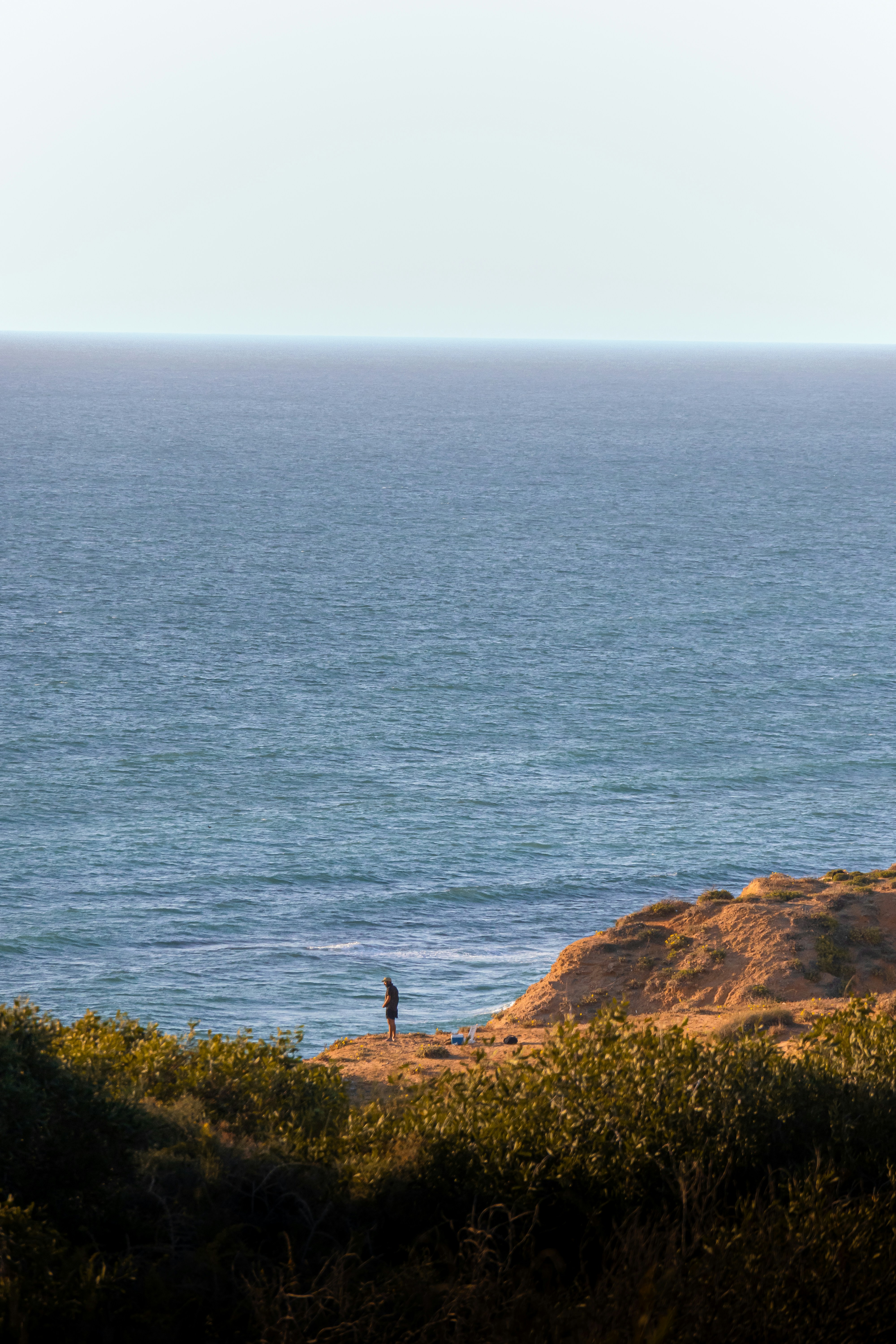 Lone Figure on the Cliff Overlooking the Quiet Sea