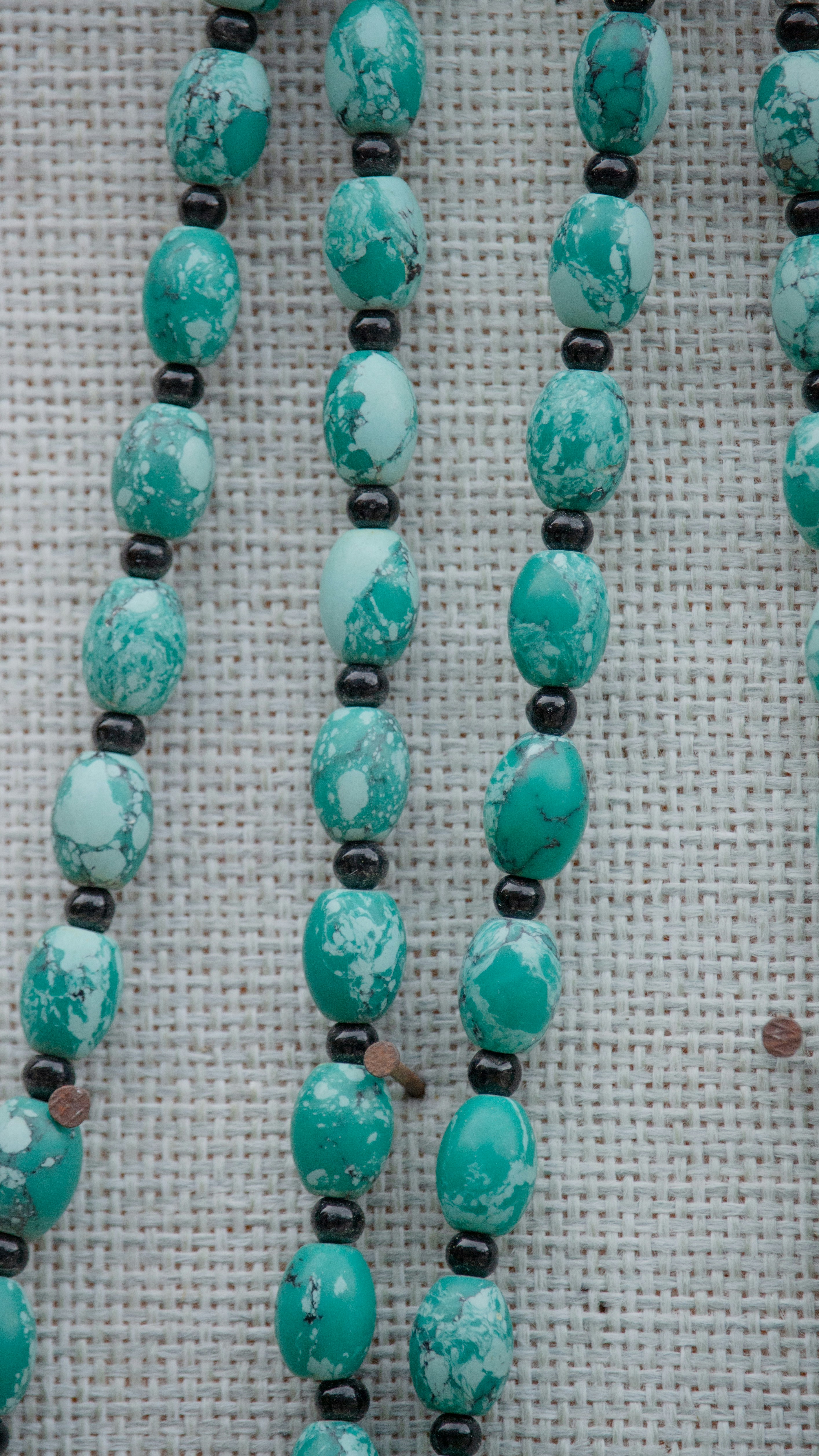 Turquoise Bead Strands Resting Against Linen