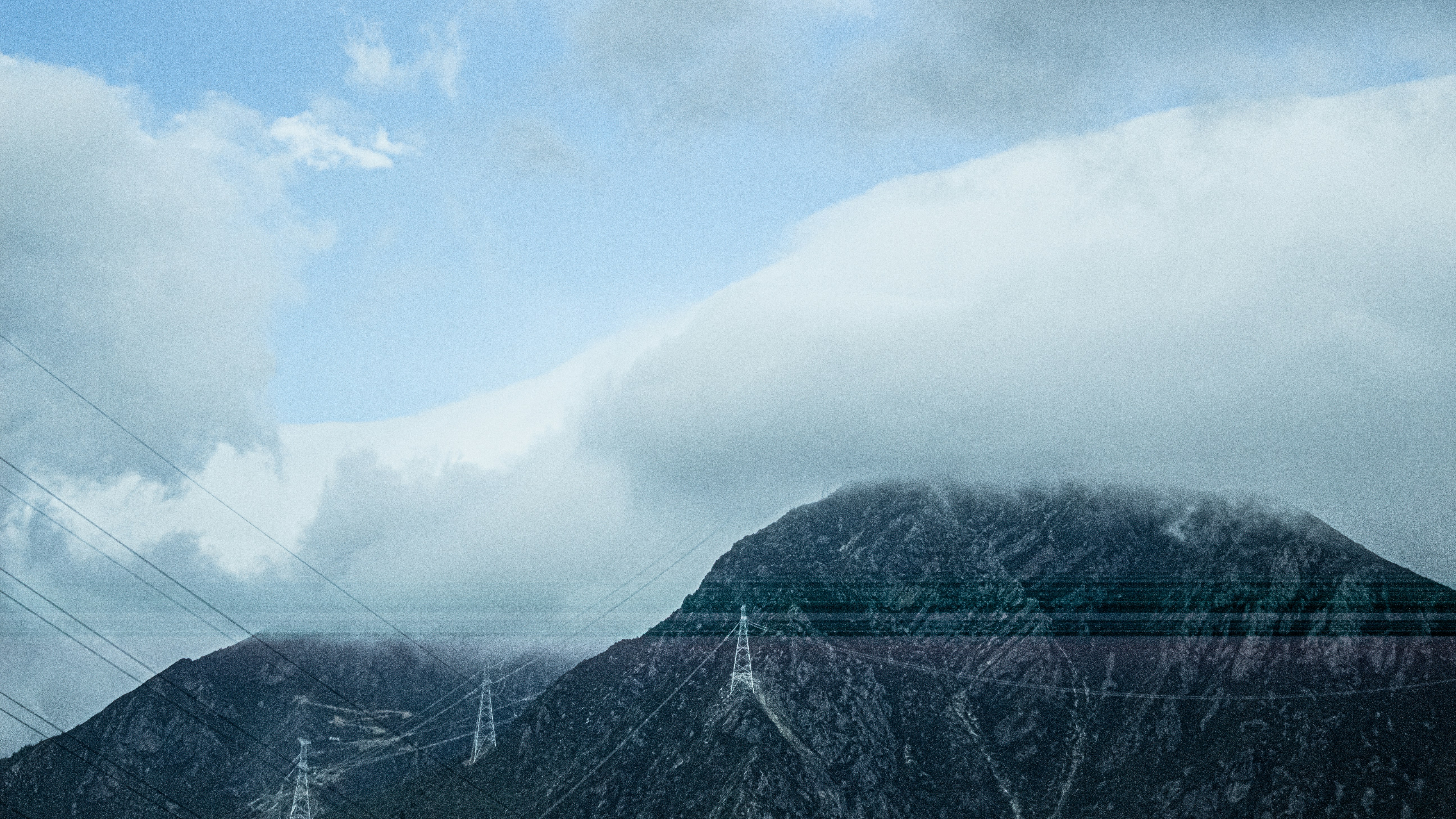Clouds Cling to the Peak: A Mountain Range under Wide Sky