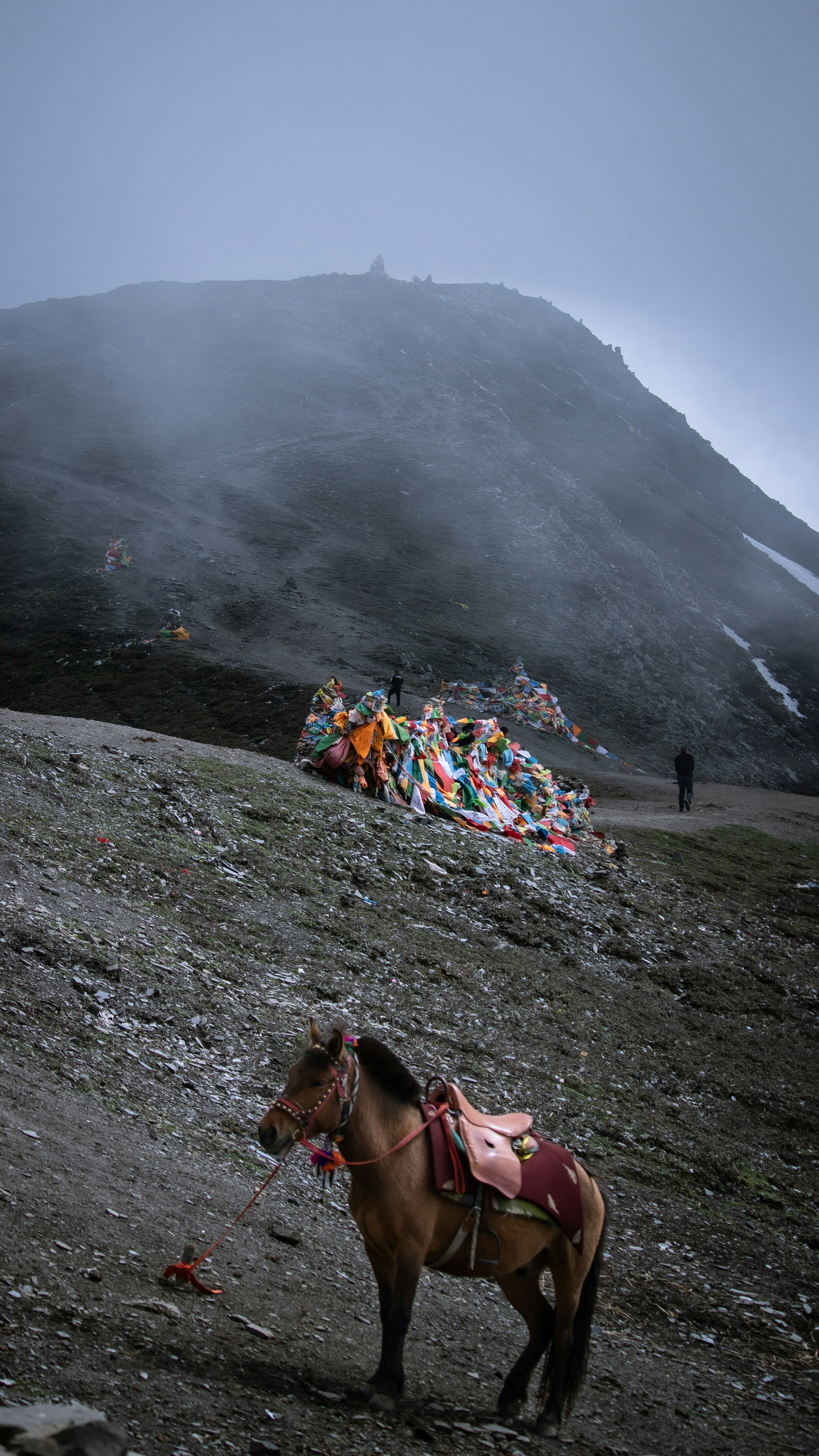 Prayer Flags and a Quiet Rider: A Mountain Path Below Misty Peaks
