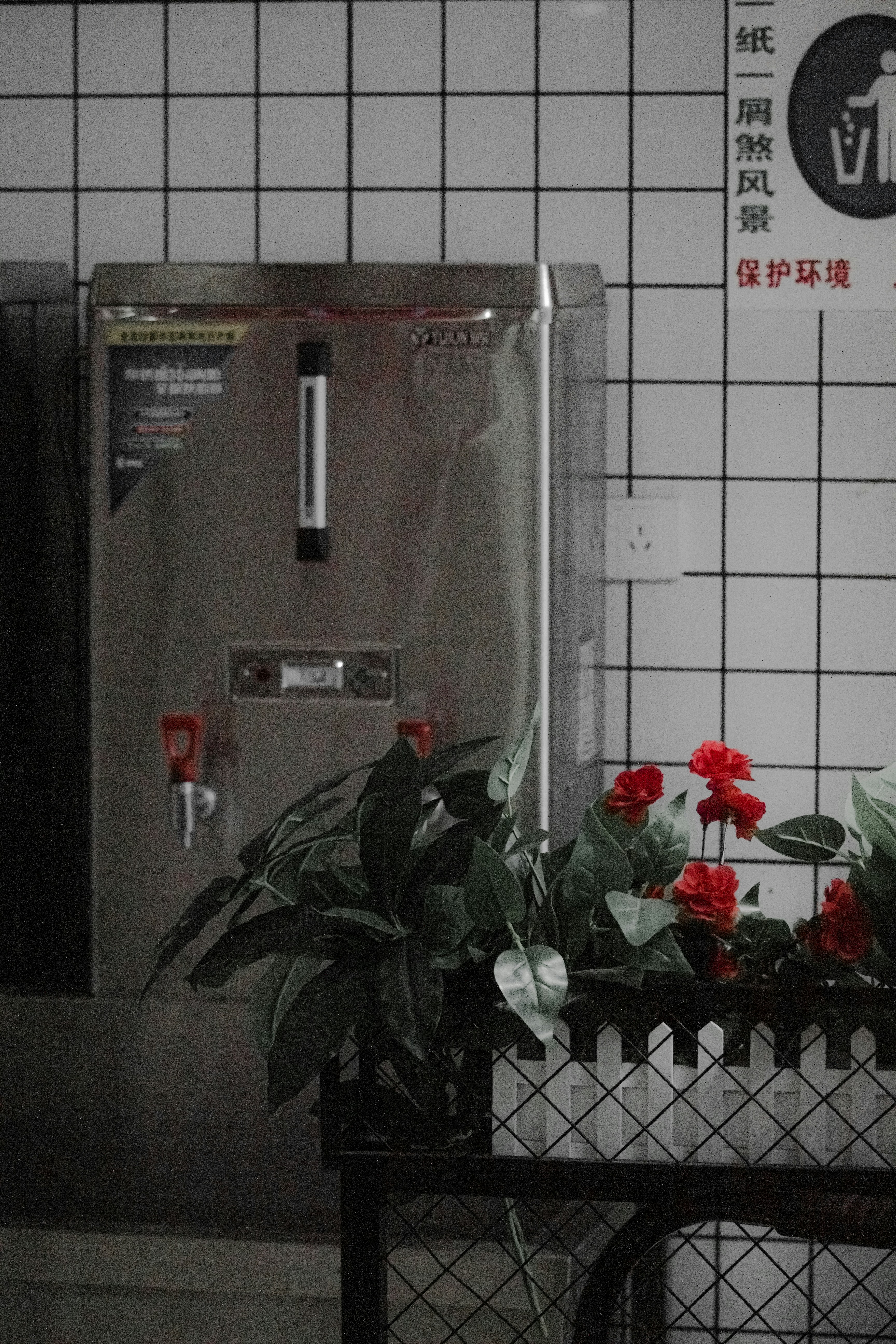 Industrial Relief: A Stainless Office Water Dispenser Framed by Red Florals