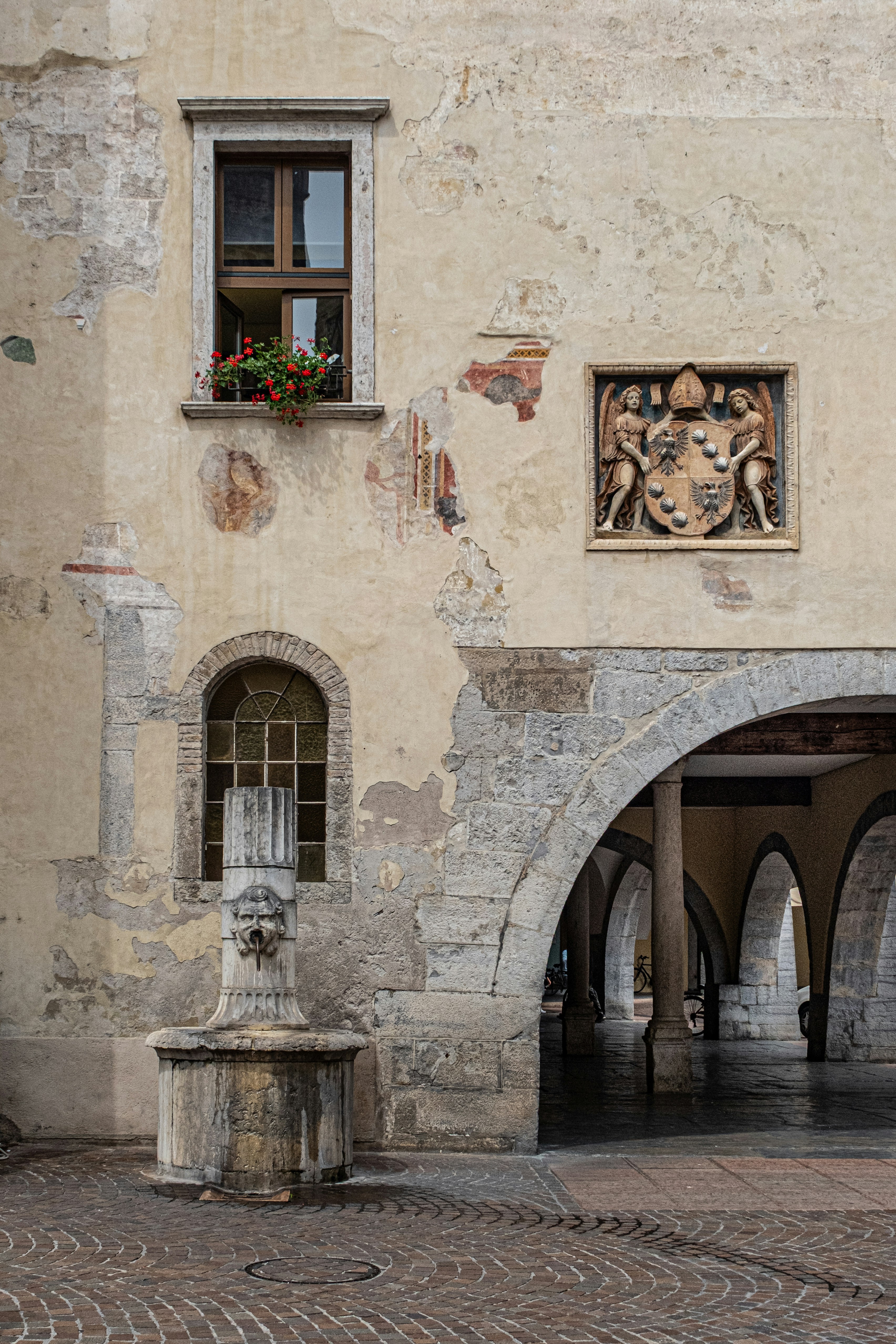 Weathered Facade and Stone Fountain Under Archway