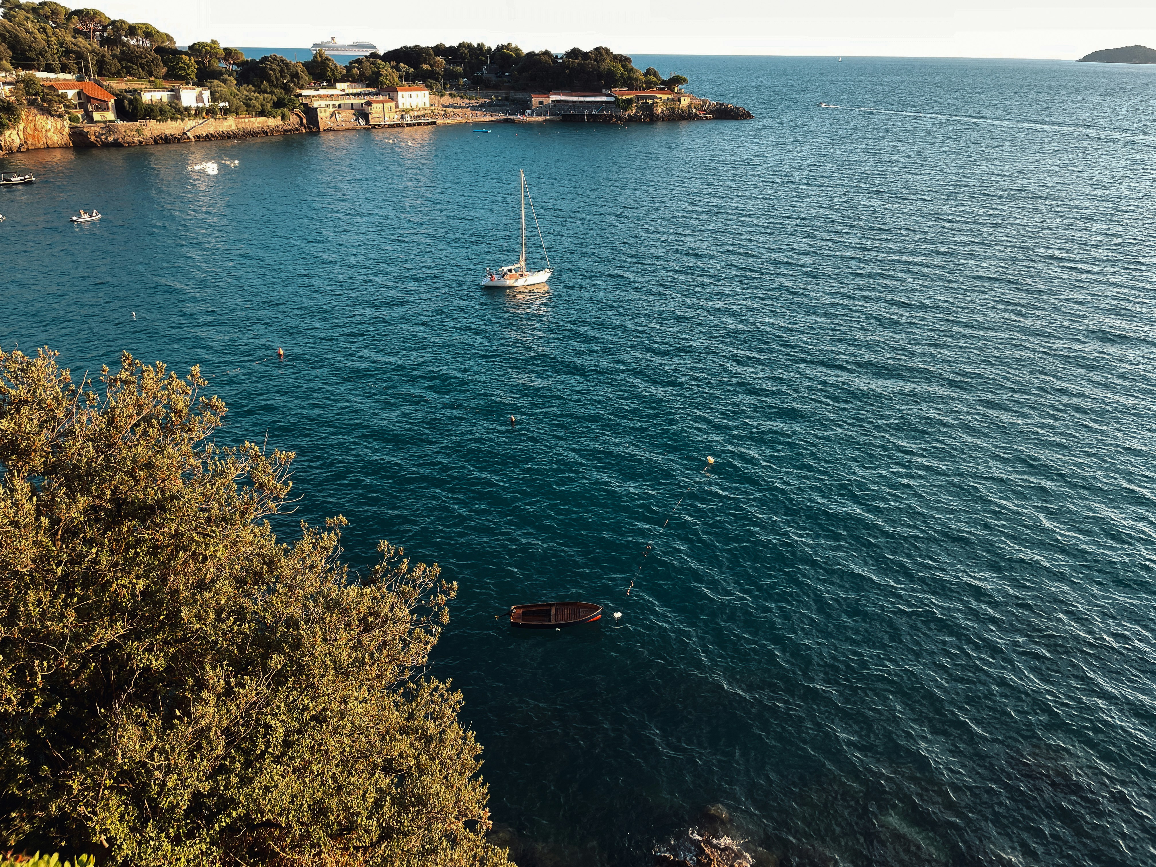 Coastal harbor with a lone sailboat under a calm afternoon sky