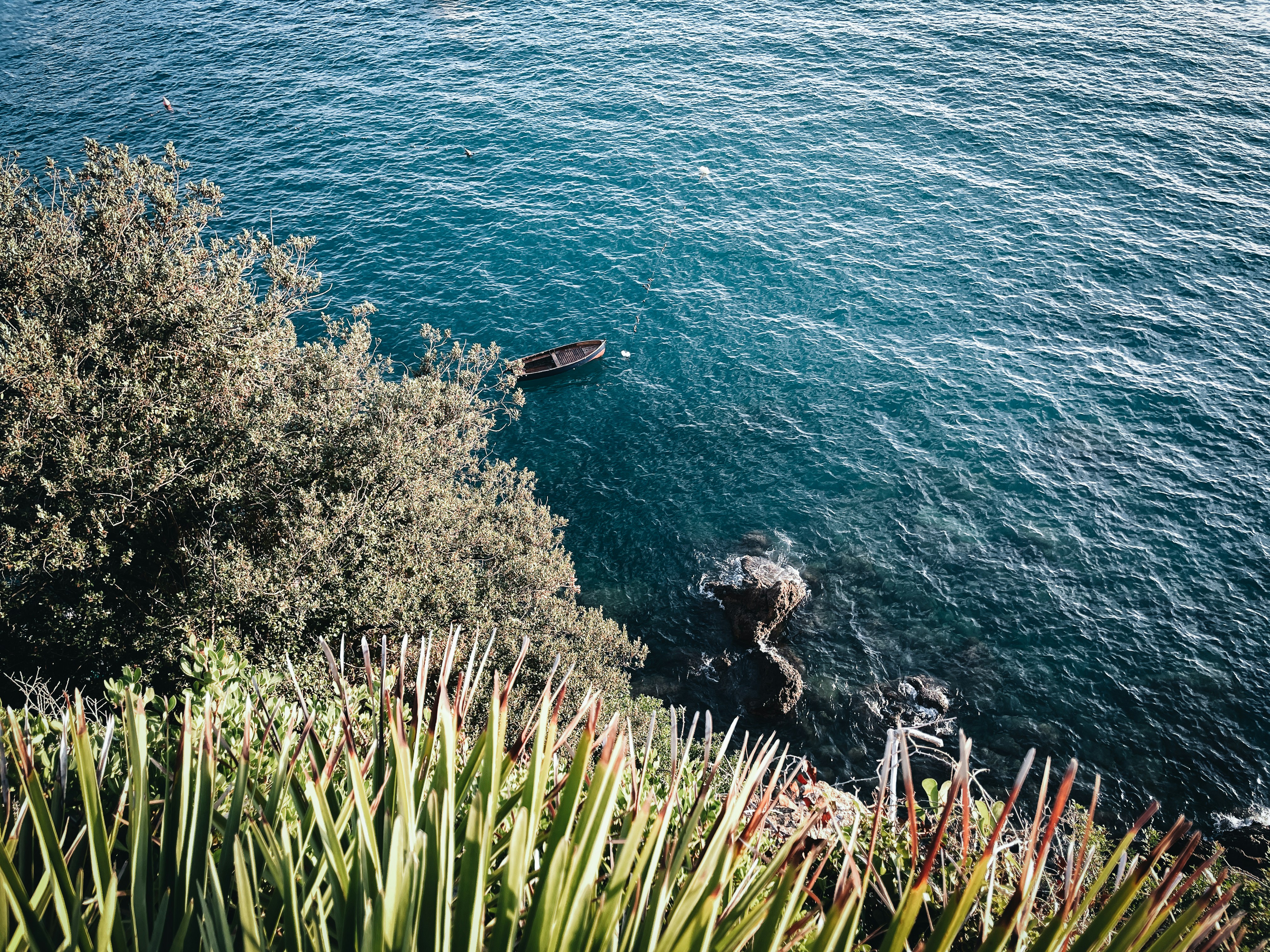 Clifftop View: A Boat resting in Turquoise Calm