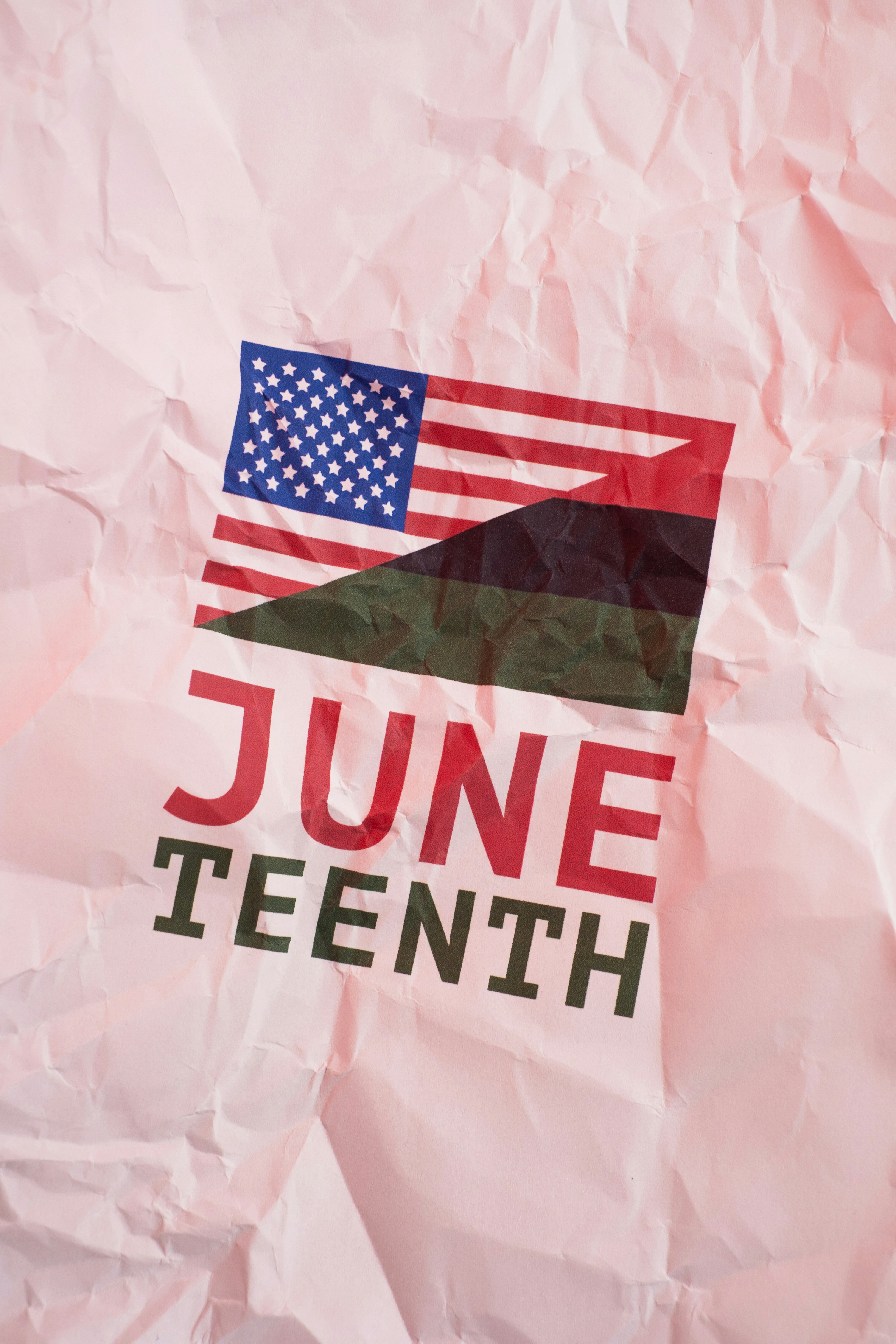Juneteenth Federal Holiday Sign with US and Pan African Split Flag on Crumpled Paper Background
