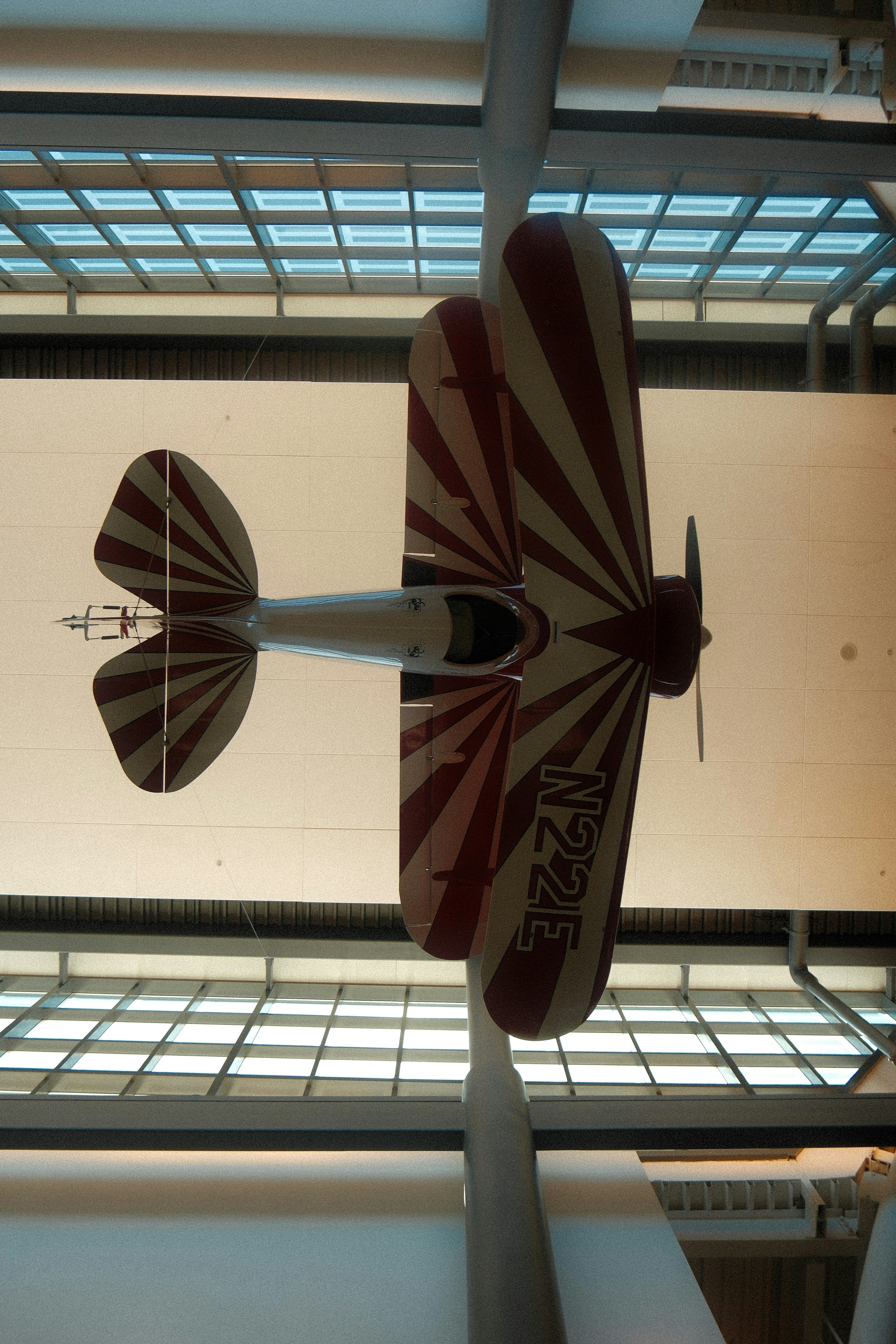 Sunburst-winged biplane suspended in a modern atrium