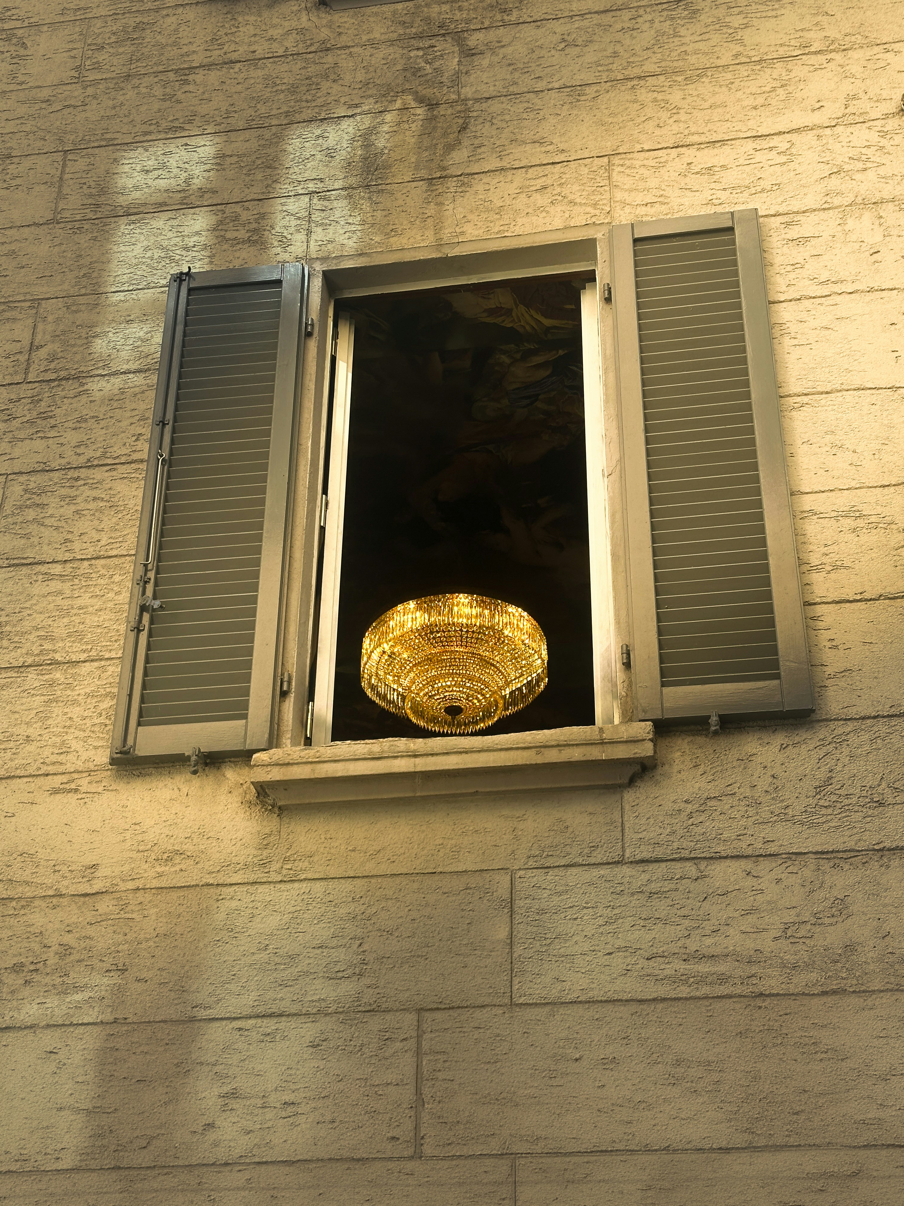 Ornate golden chandelier glowing in an open window.