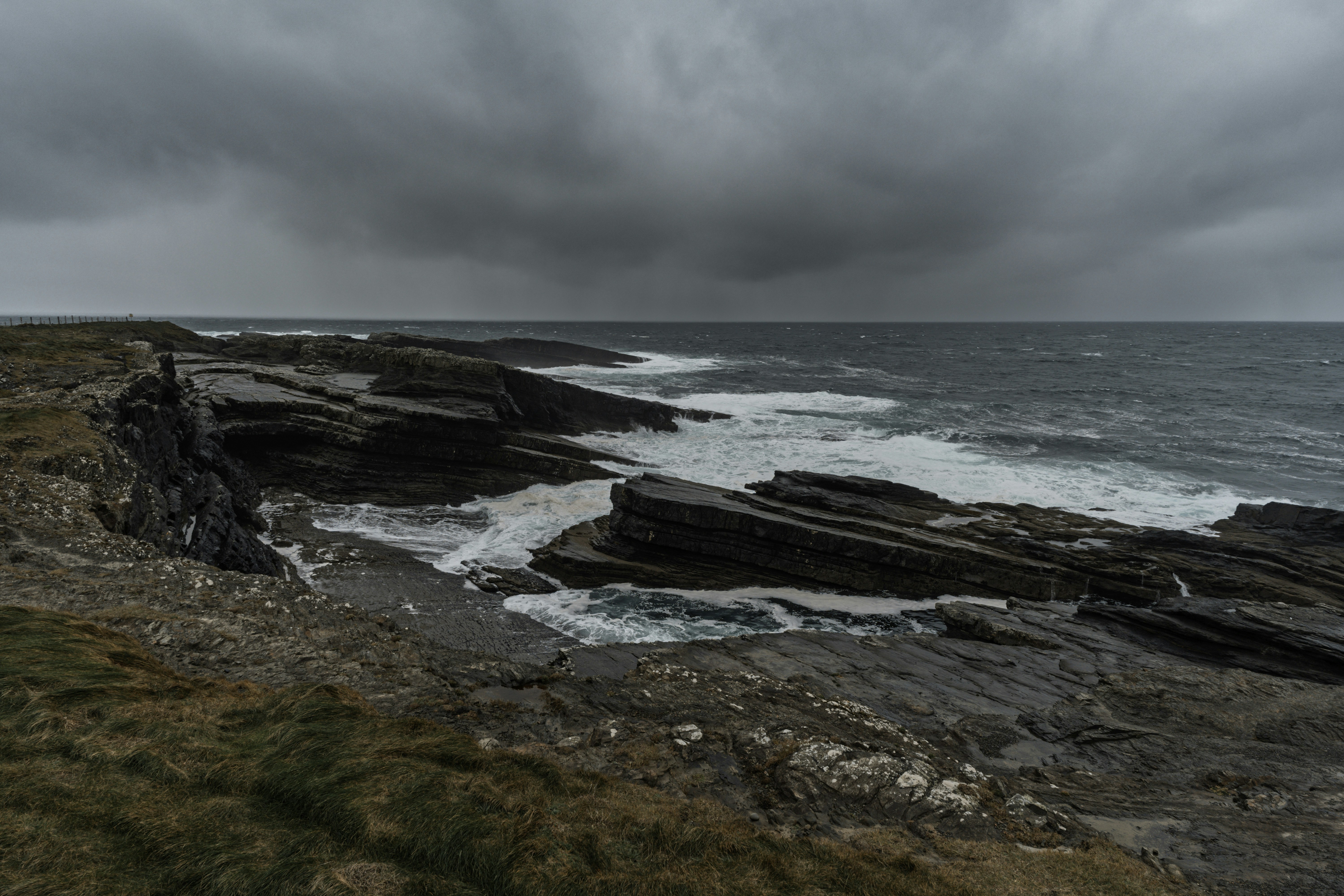 Storm-Lashed Cliffs: Rocky Shore Under Heavy Skies