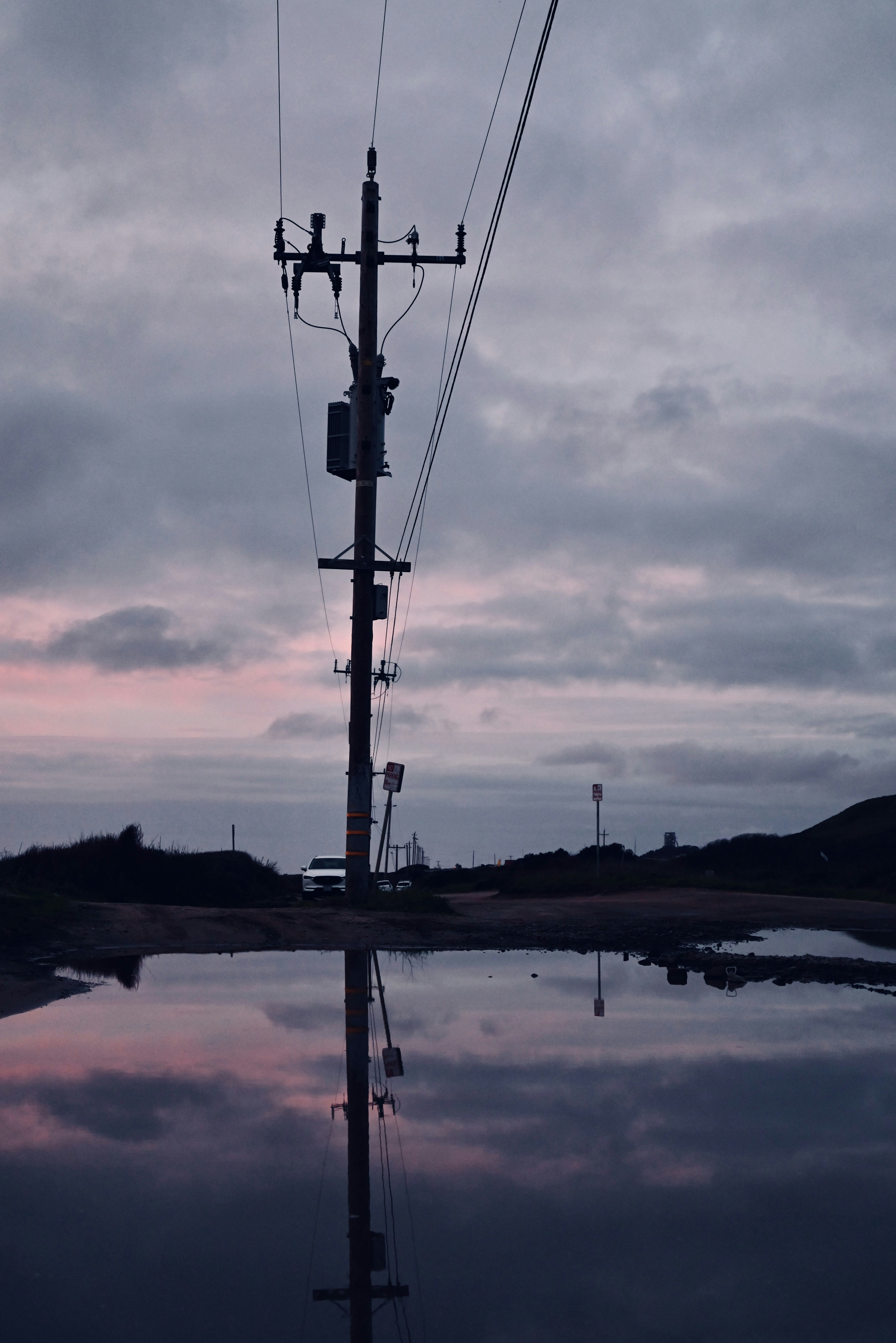 Silhouette of a Utility Pole at Sunset, Reflected in a Calmed Wet Ground