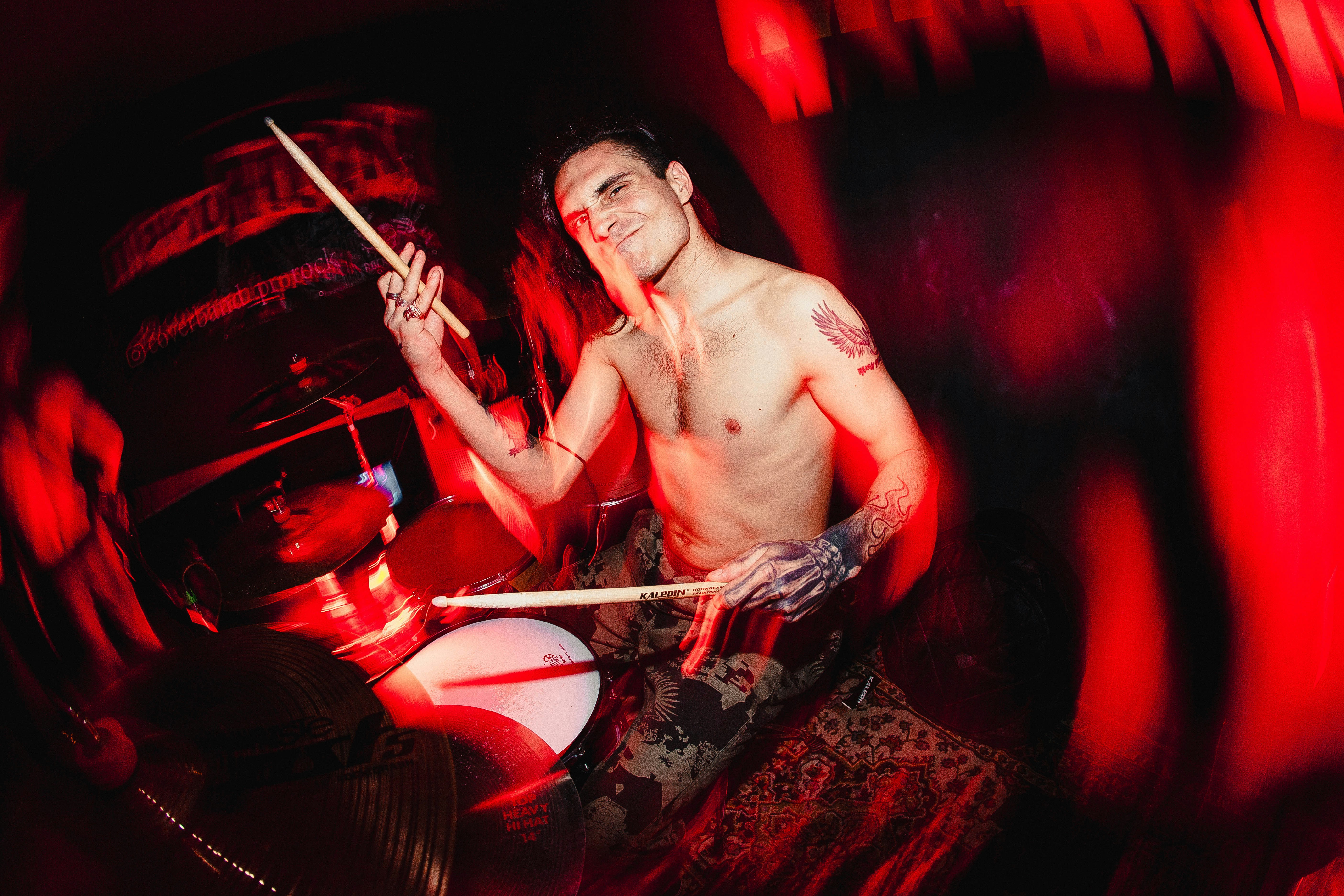 Drums Under Red Lights: A Shirtless Performer Surges with Energy