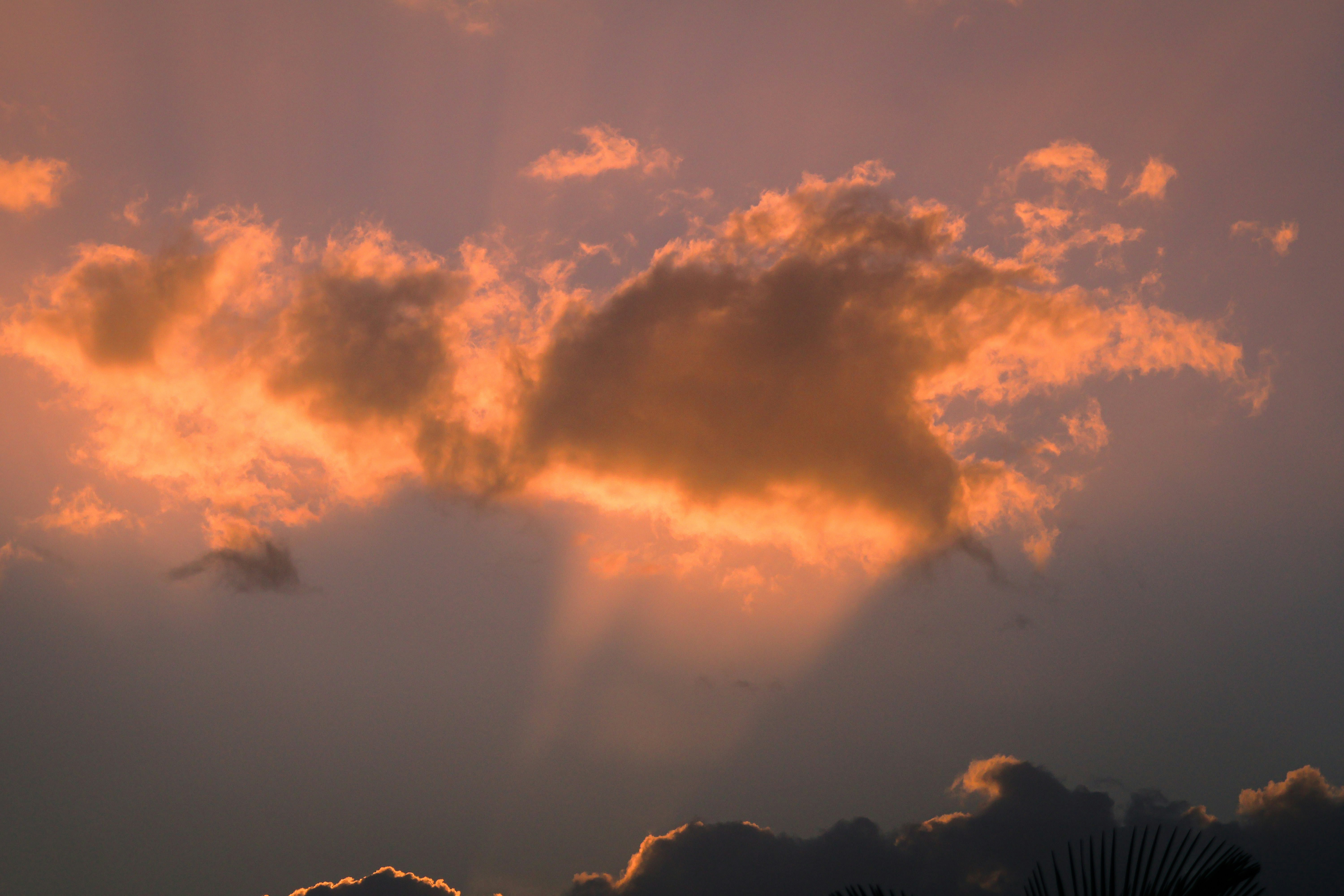 Sunset Breakthrough: A Glowing Cloud and Silhouetted Horizon