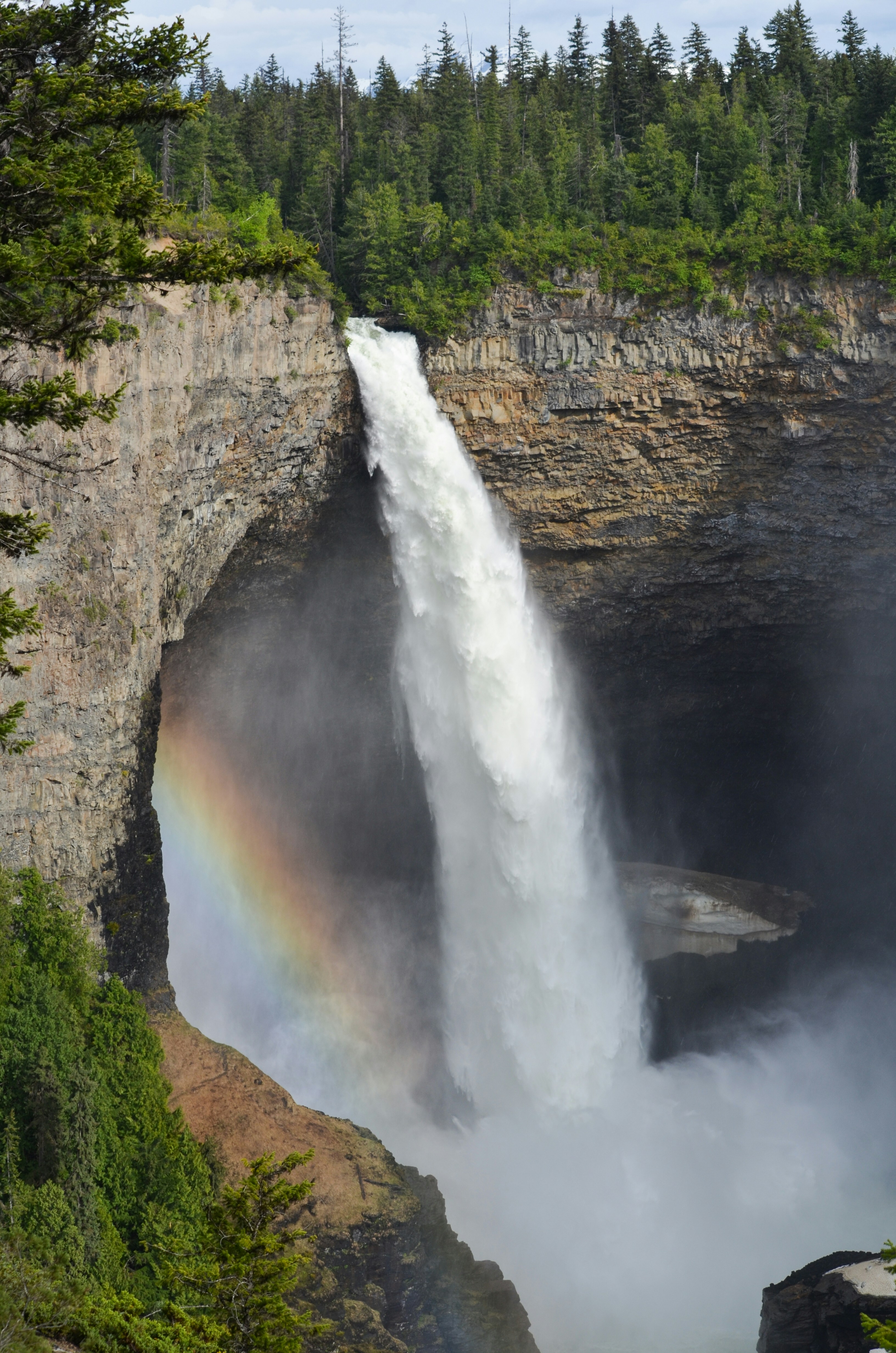 Rainbow beneath a roaring waterfall at cliff's edge