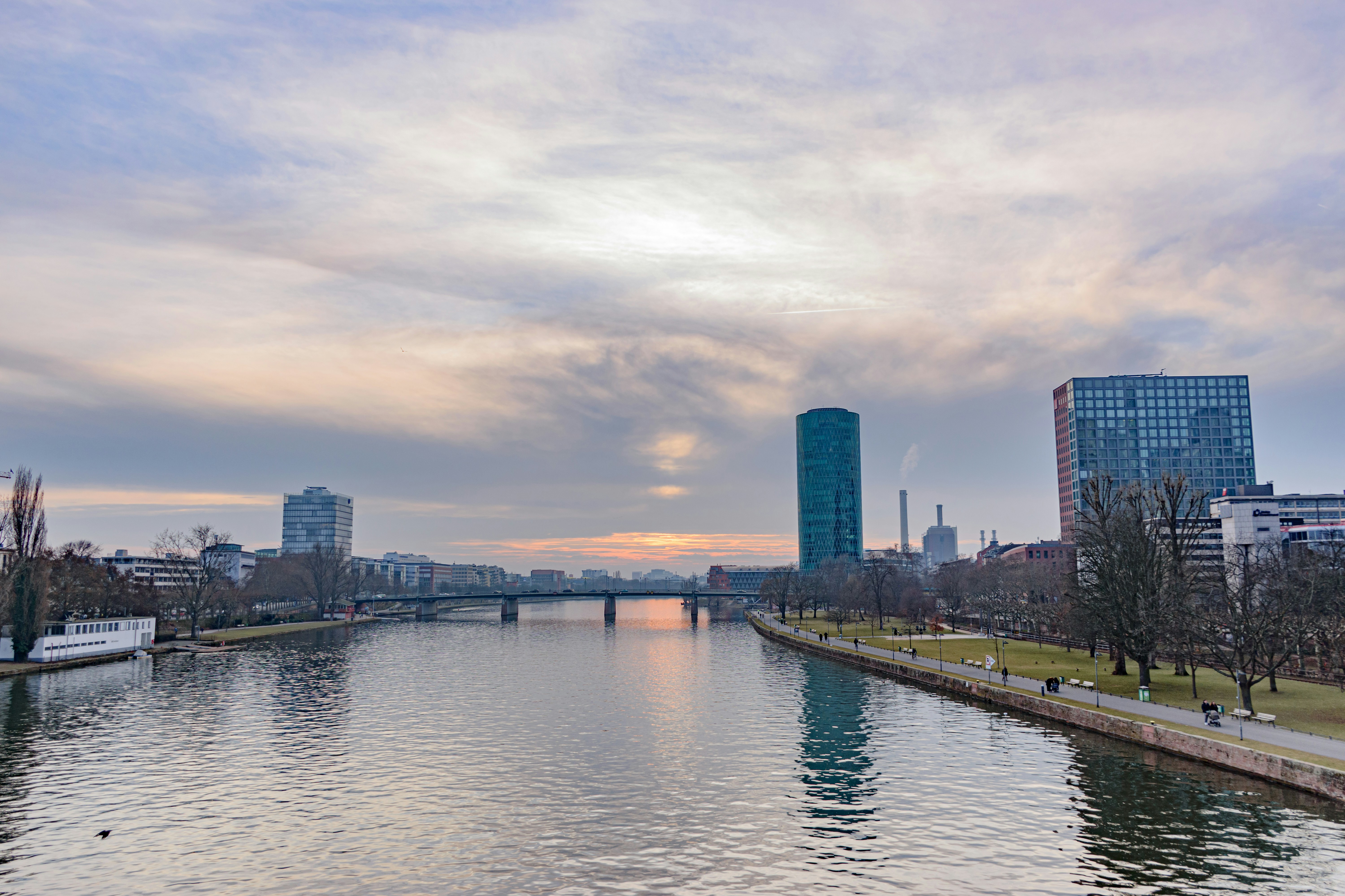 Urban river landscape with a bridge and buildings at sunset.