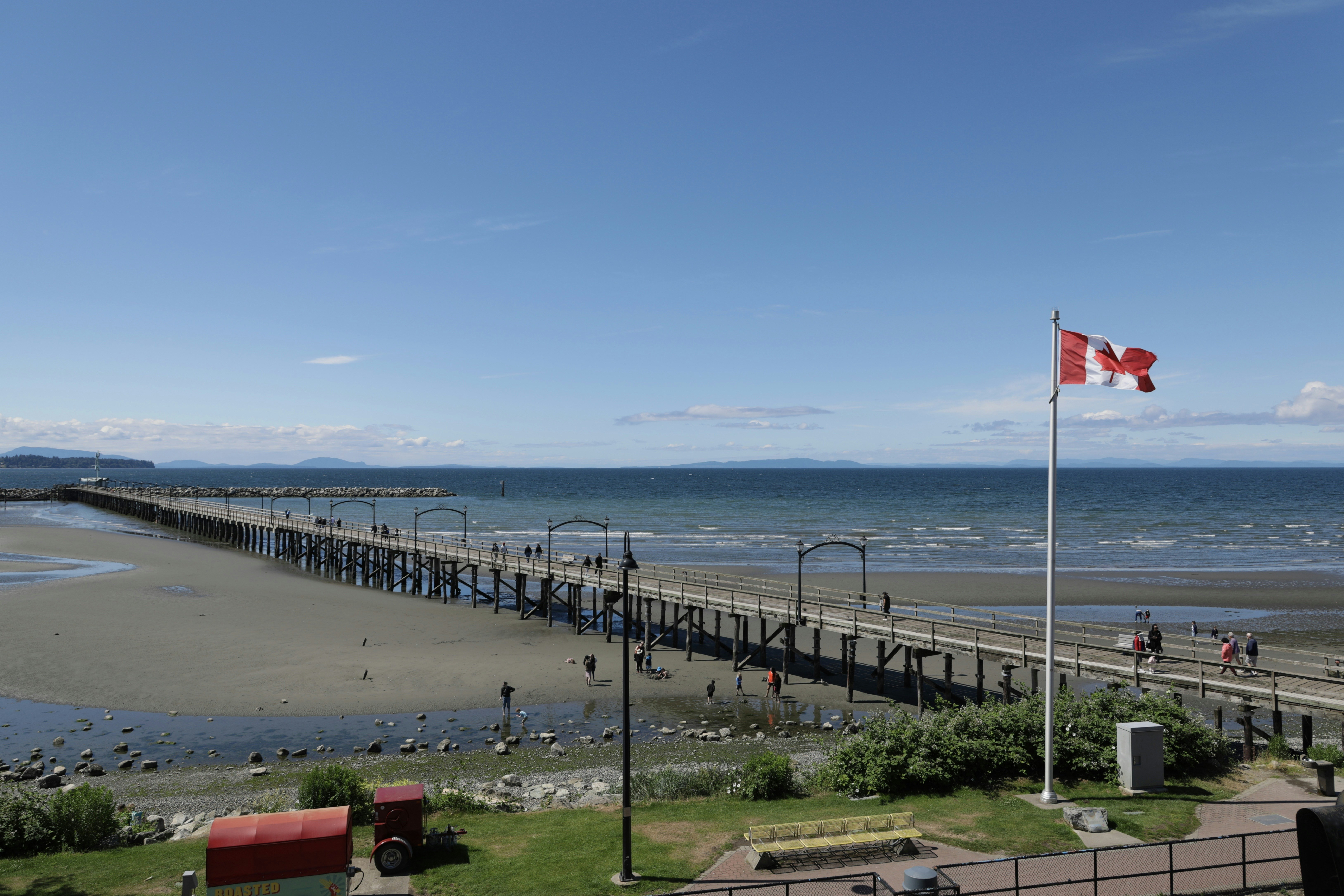 Canadian Tide: Pier Reaches into Blue Horizon Under a Flag