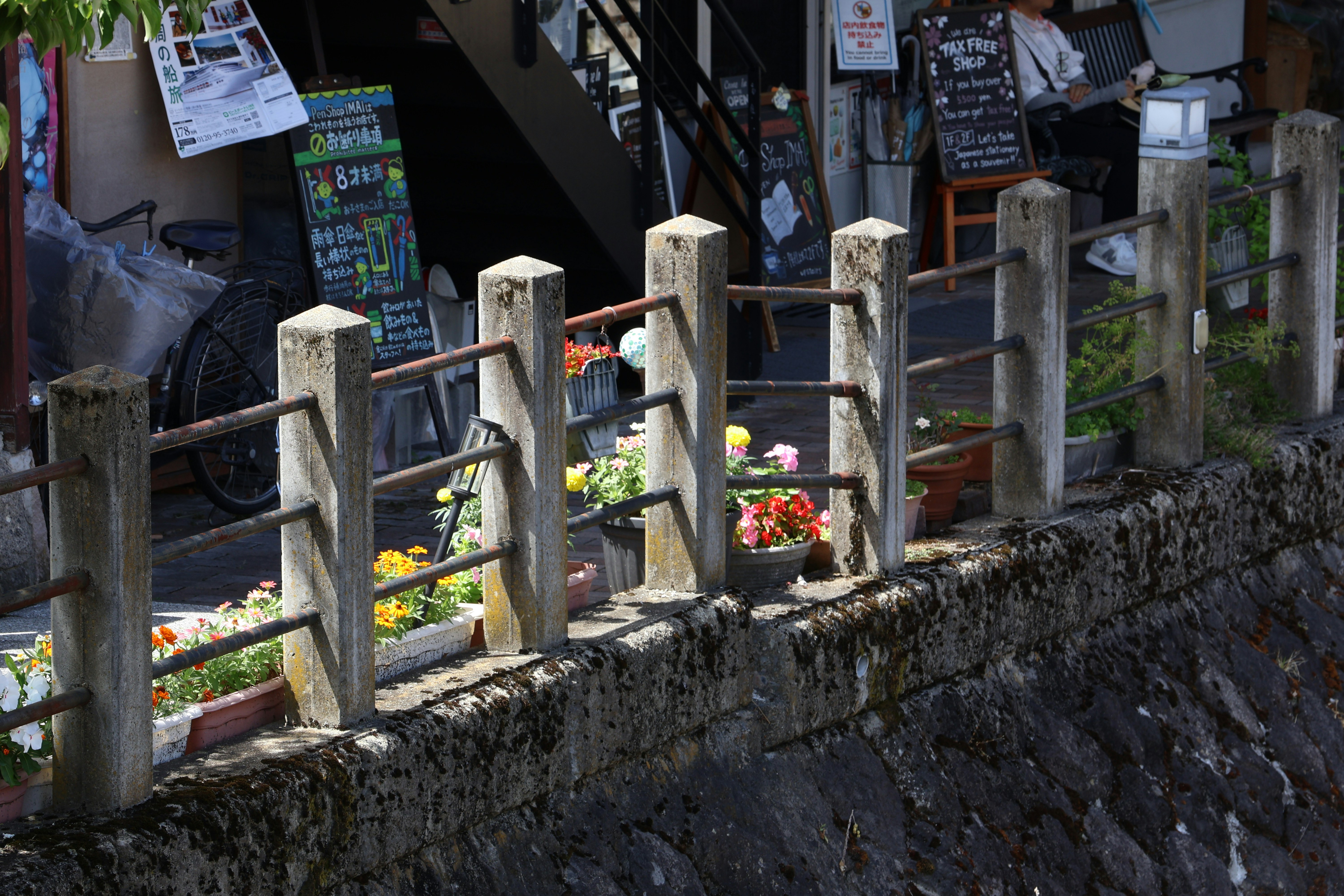 Railing Garden: Flowers and cafe signage along a stone edge