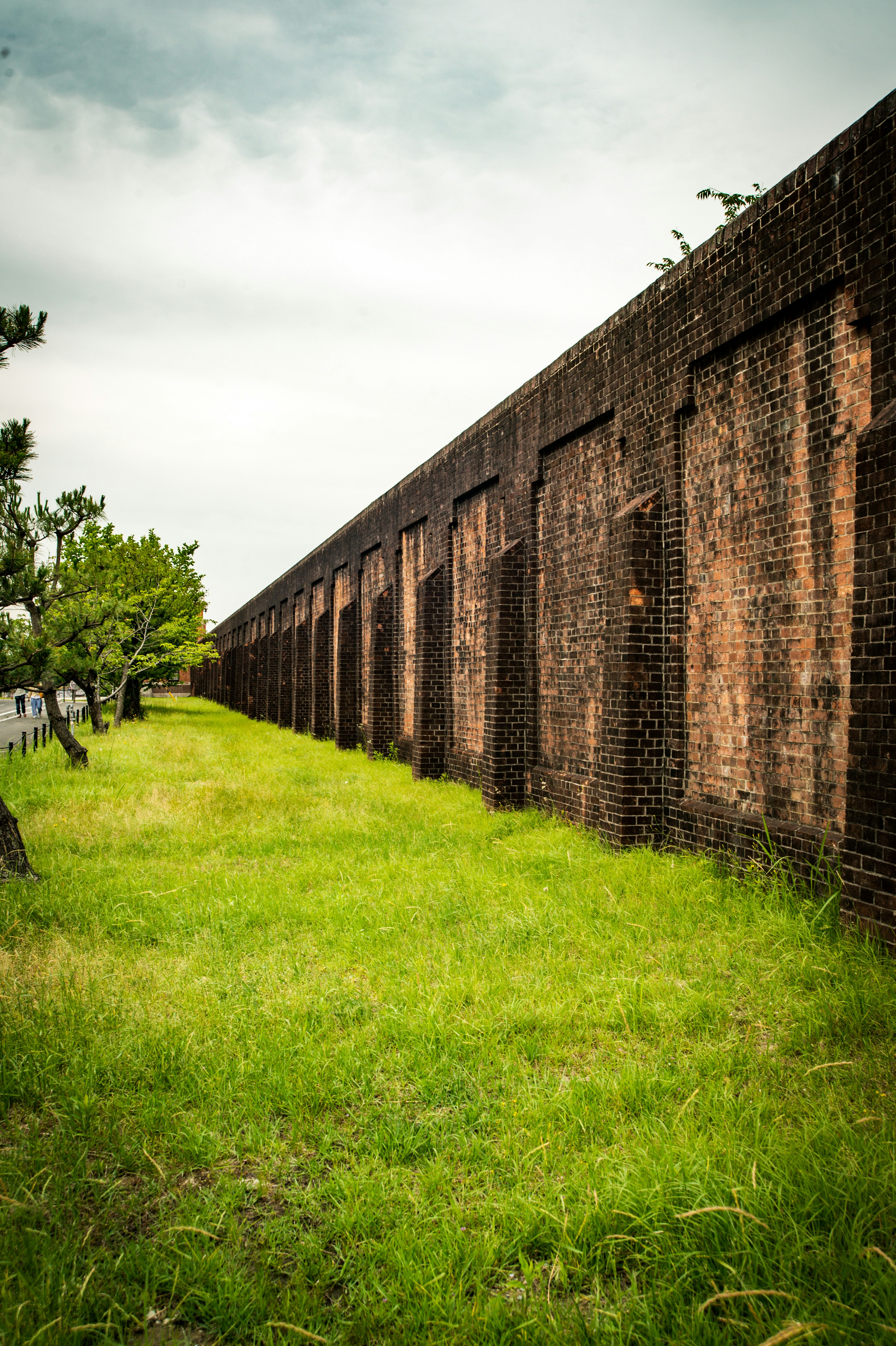 Long Brick Wall Ascending from Grass-Soaked Field