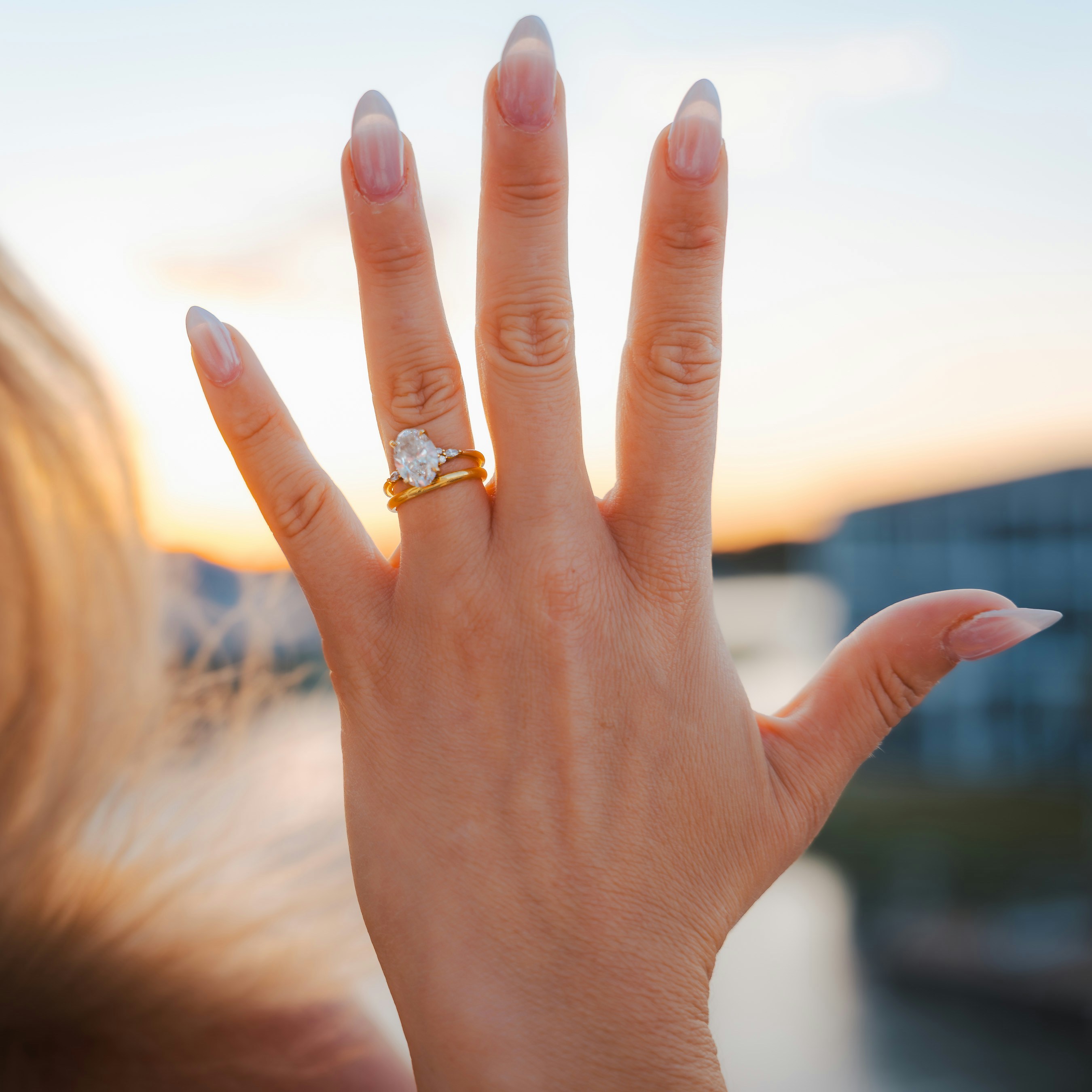 Diamond engagement ring on a hand at sunset.