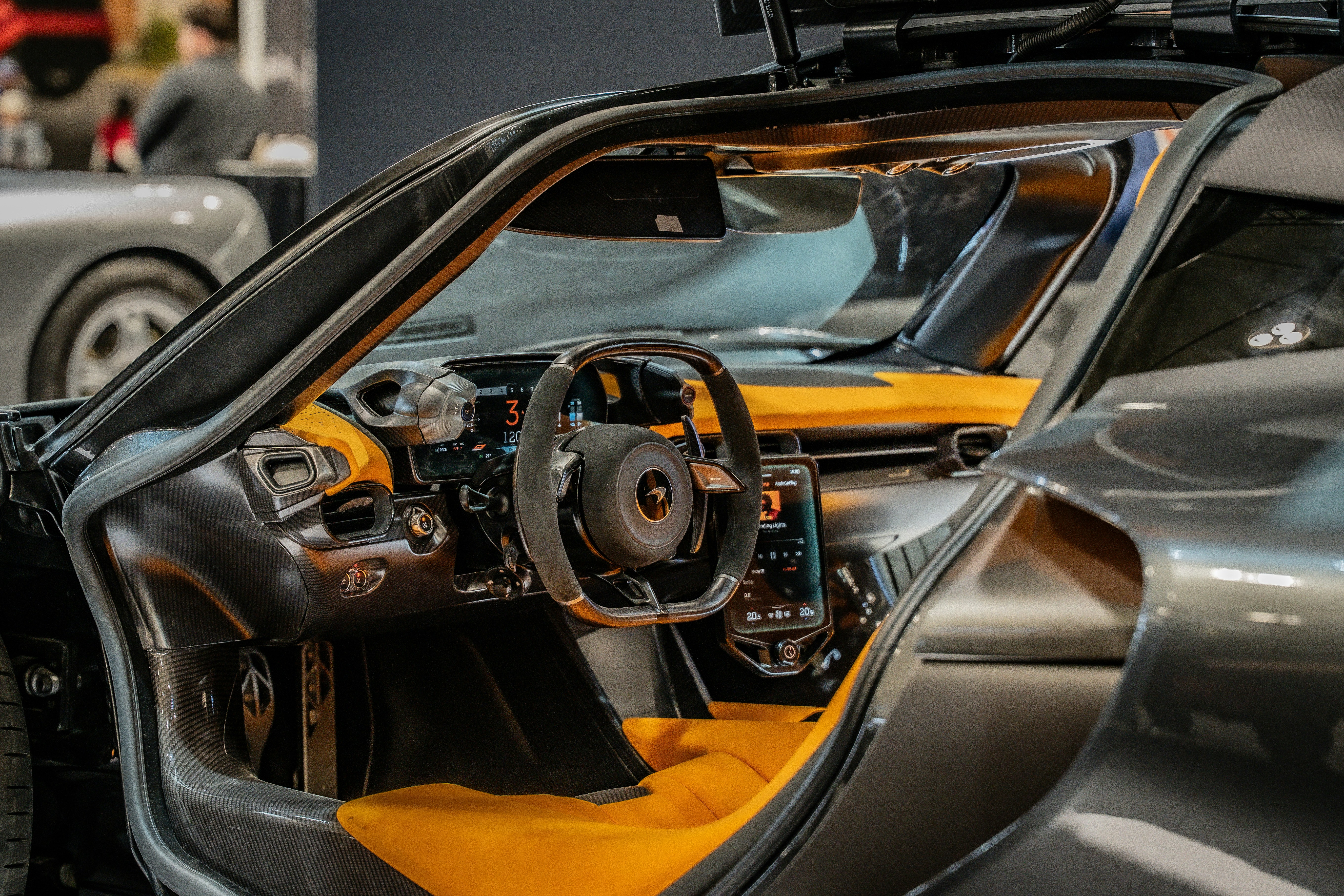 Orange stitched cockpit: a supercar interior with a racing steer and open door