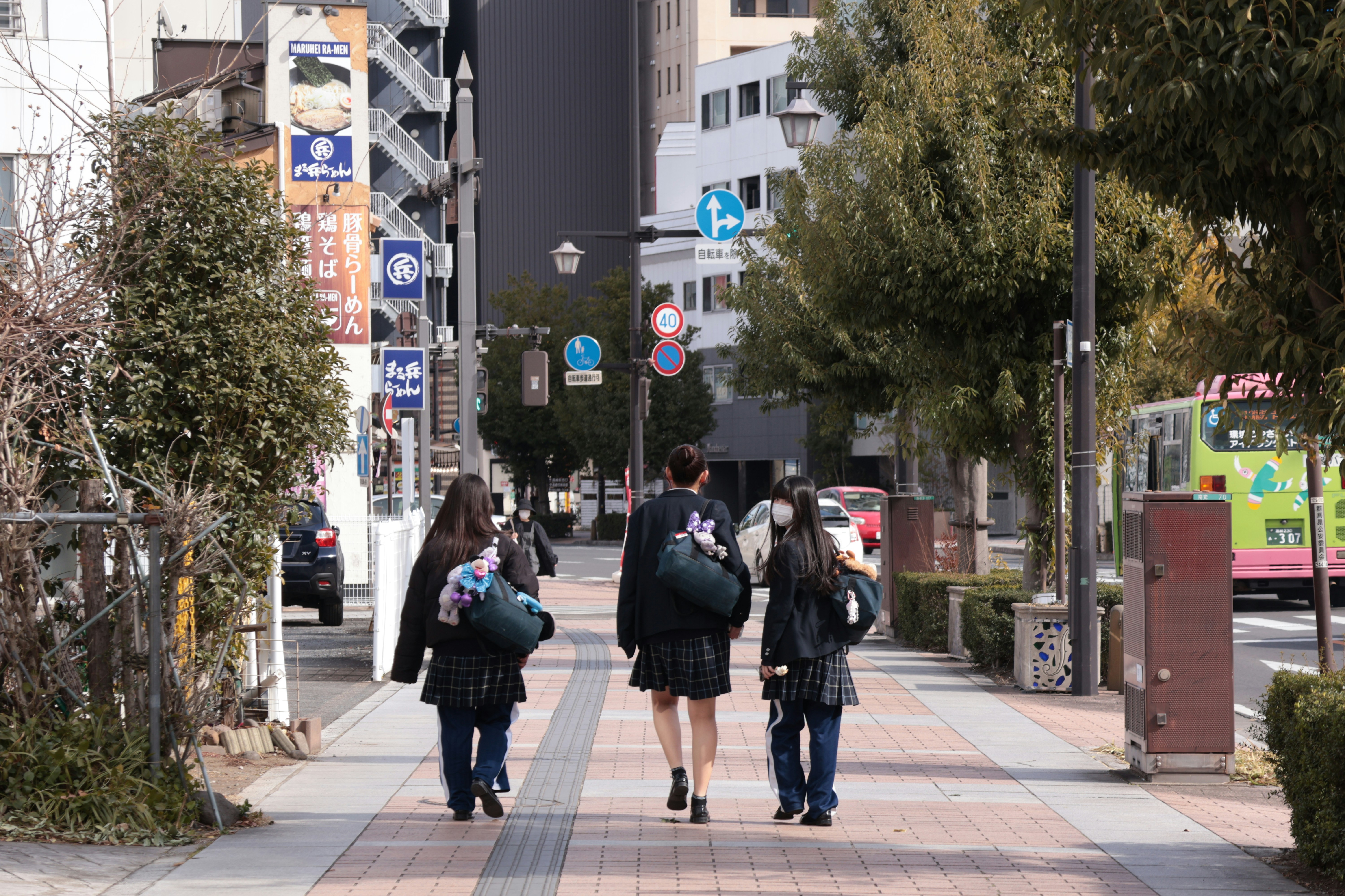Three people walking on a city sidewalk.