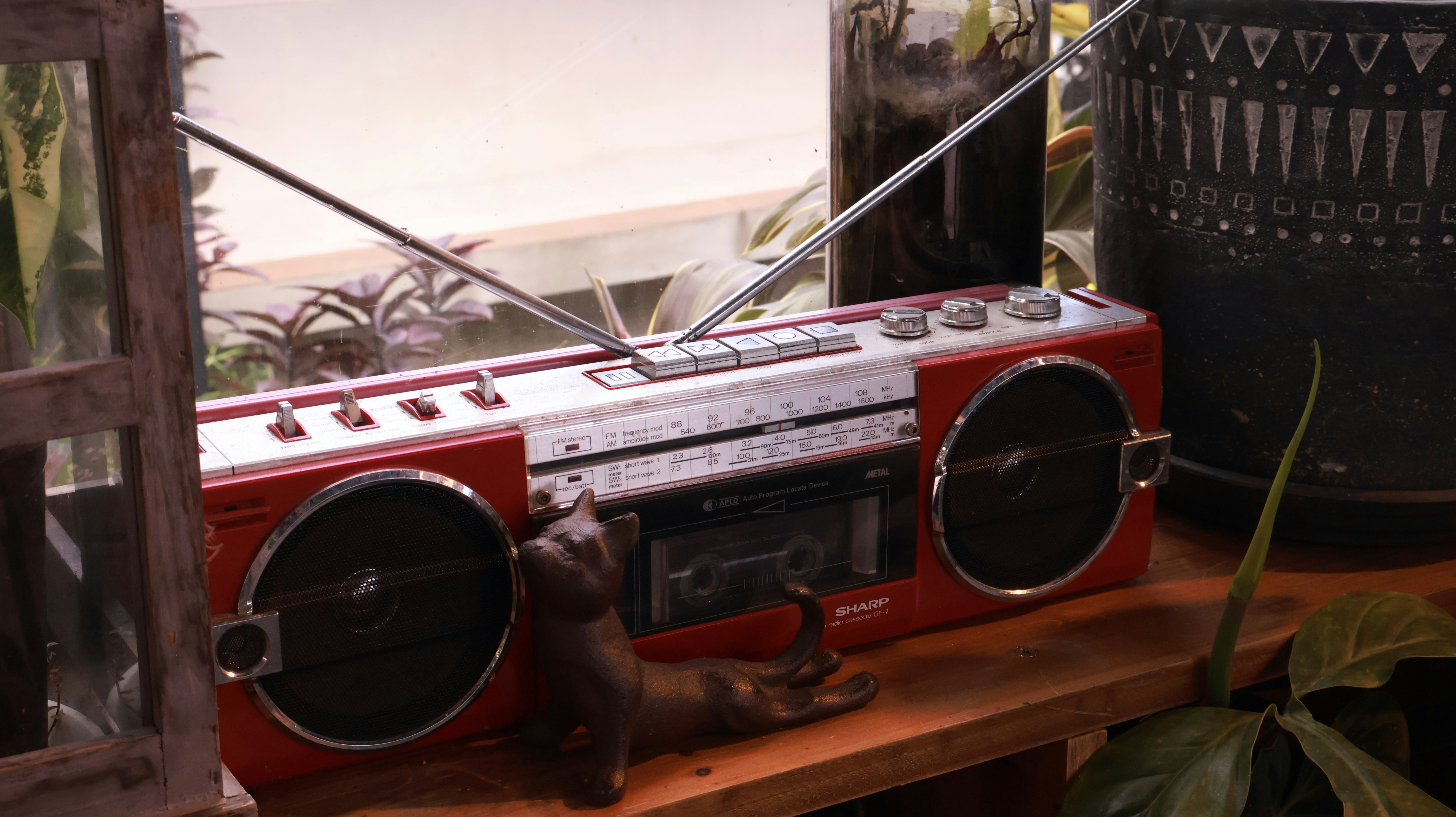 A red vintage boombox on a wooden shelf.