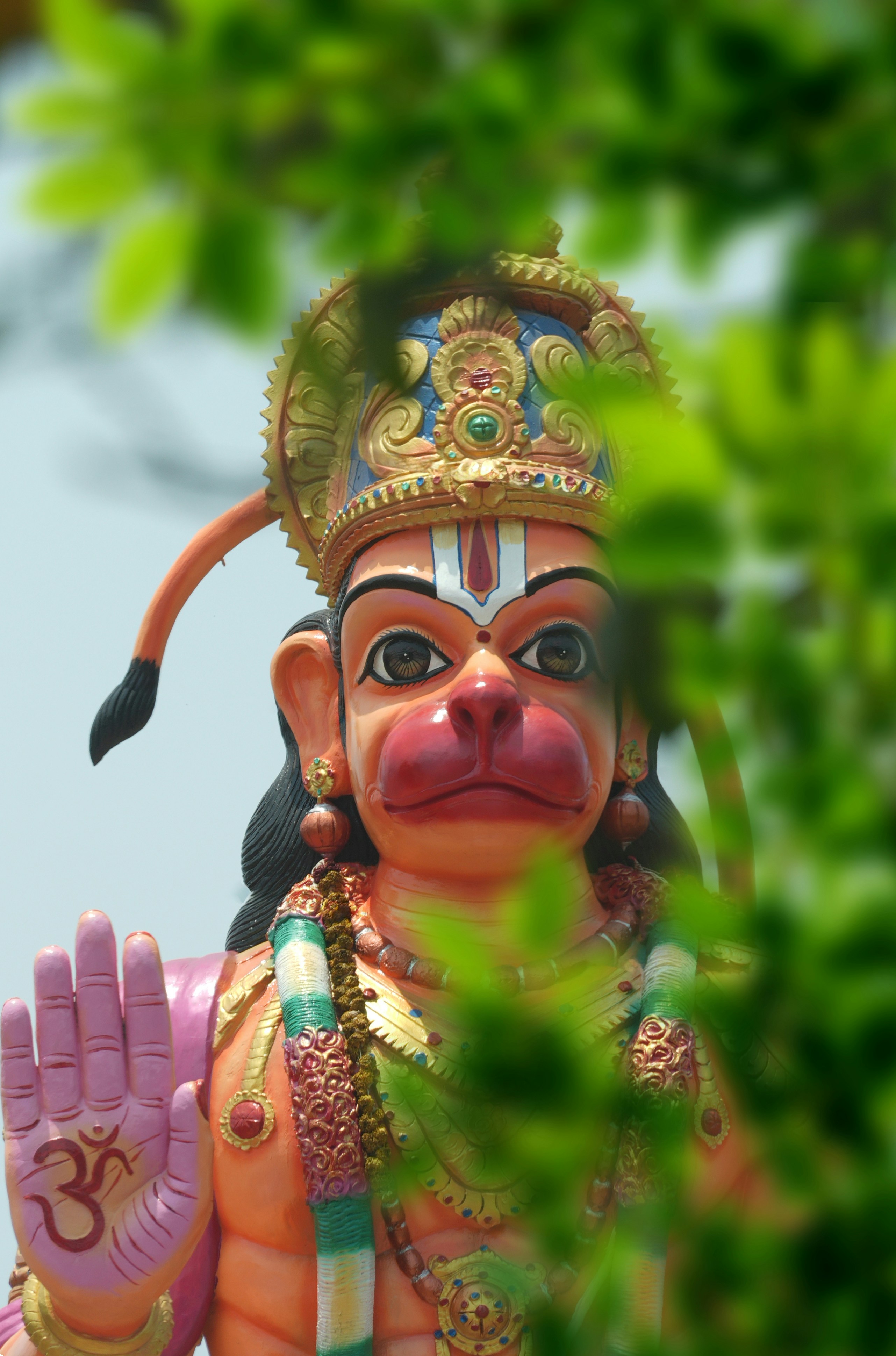 Vibrant hanuman statue with om symbol on raised hand.