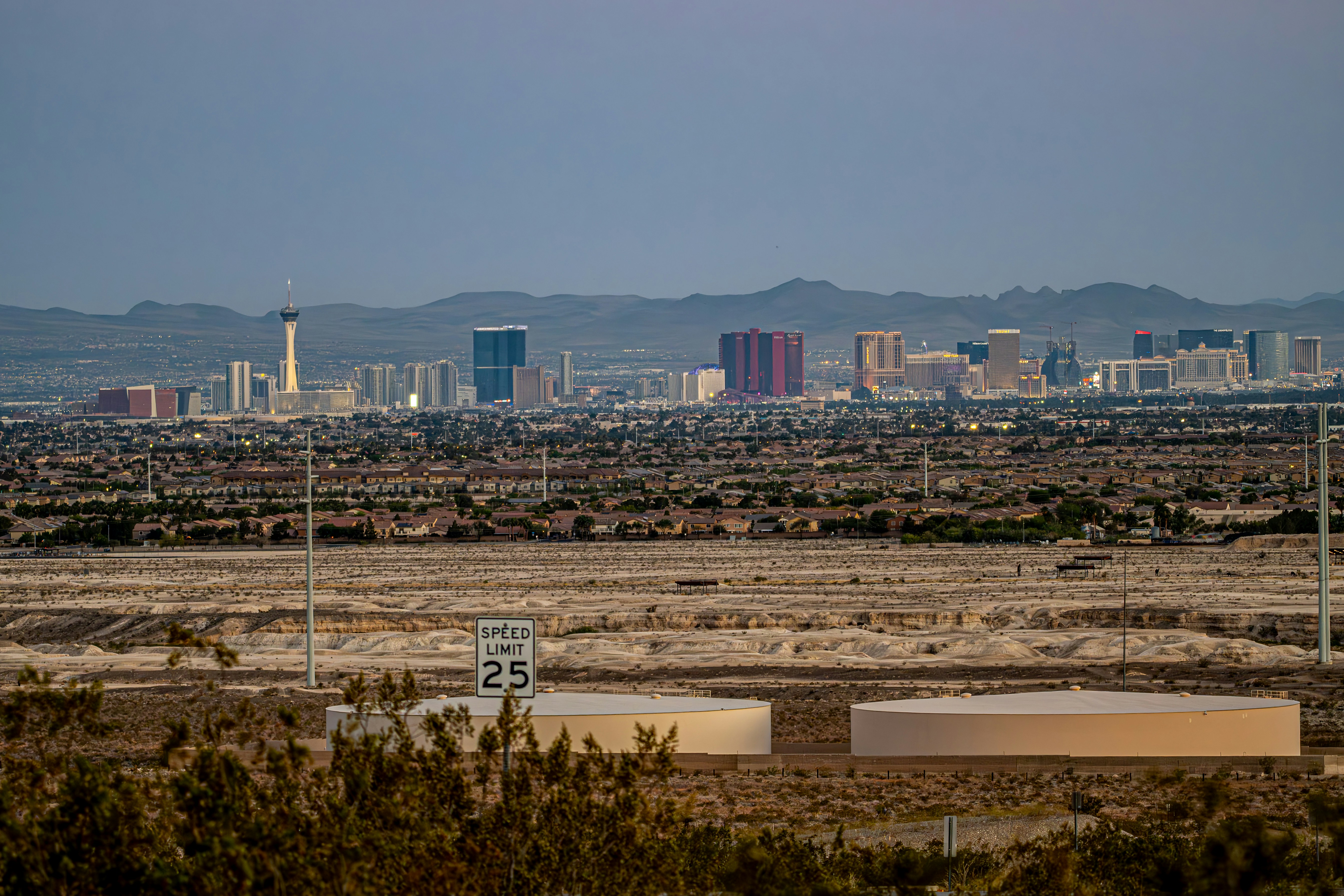 Las vegas skyline over a desert landscape with storage tanks.