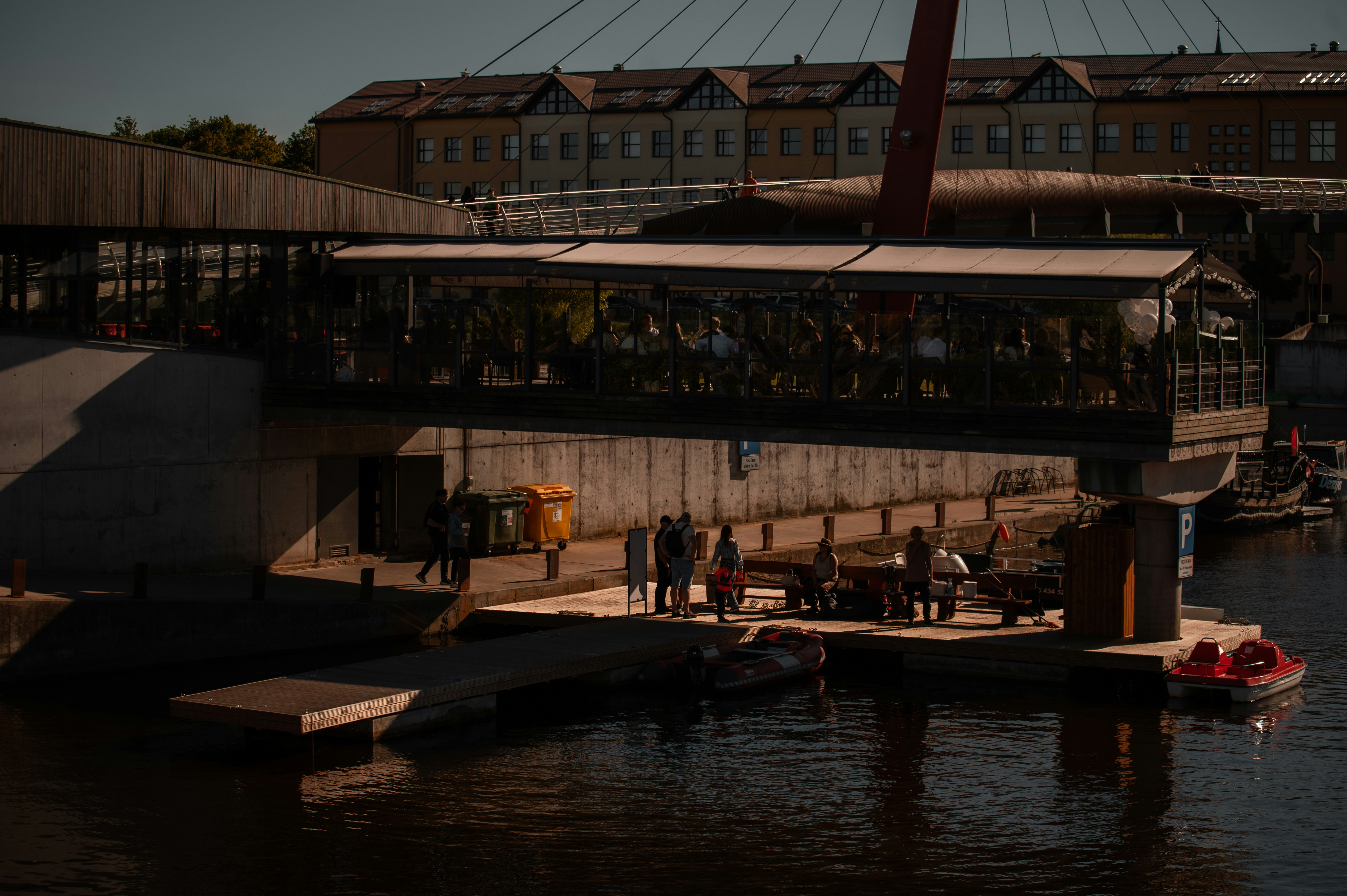 Industrial waterfront terrace at dusk with a covered viewing deck over calm water