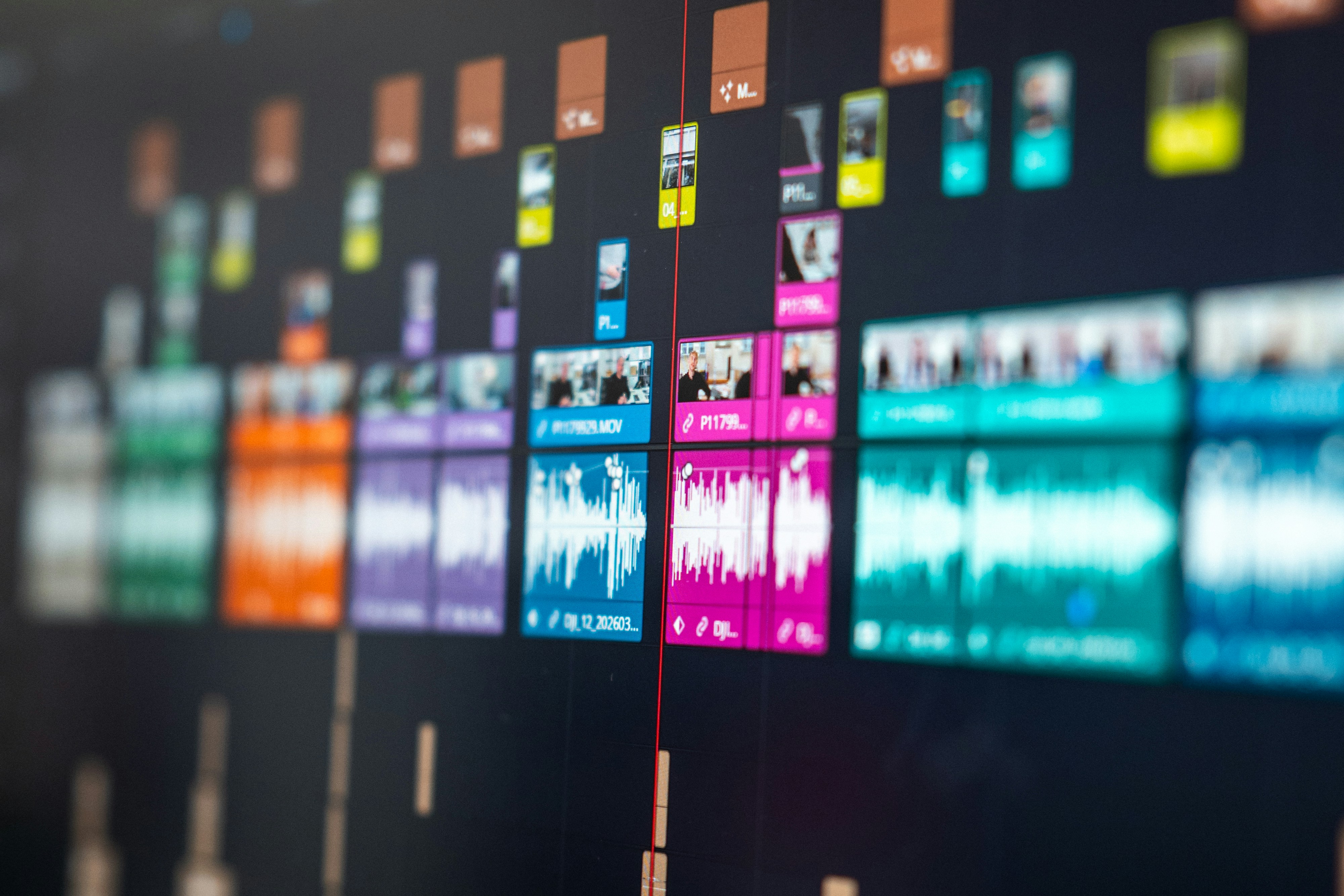 Colorful video editing timeline with audio waveforms and video clips.