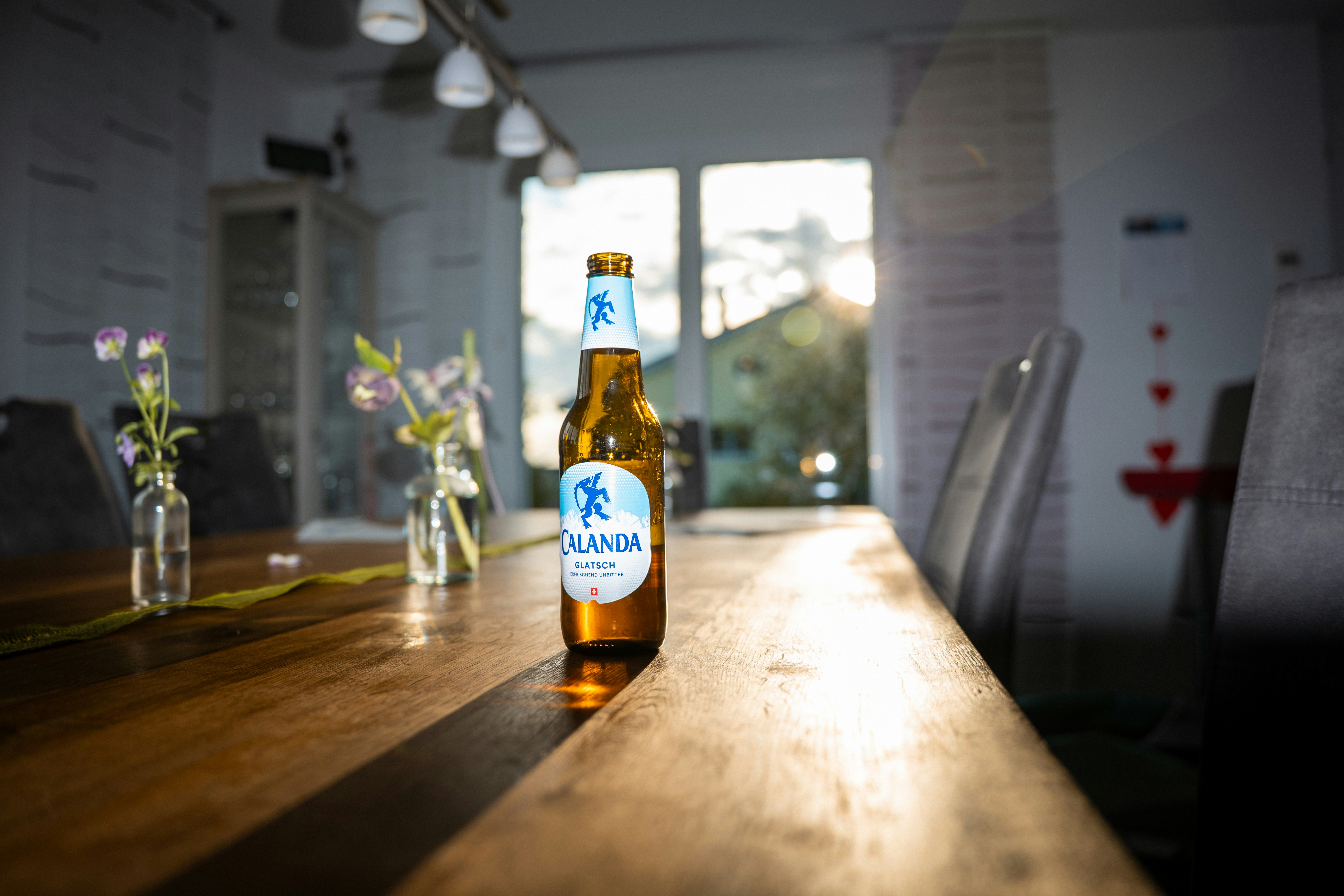 An "islanda" beer bottle on a wooden table in sunlight.