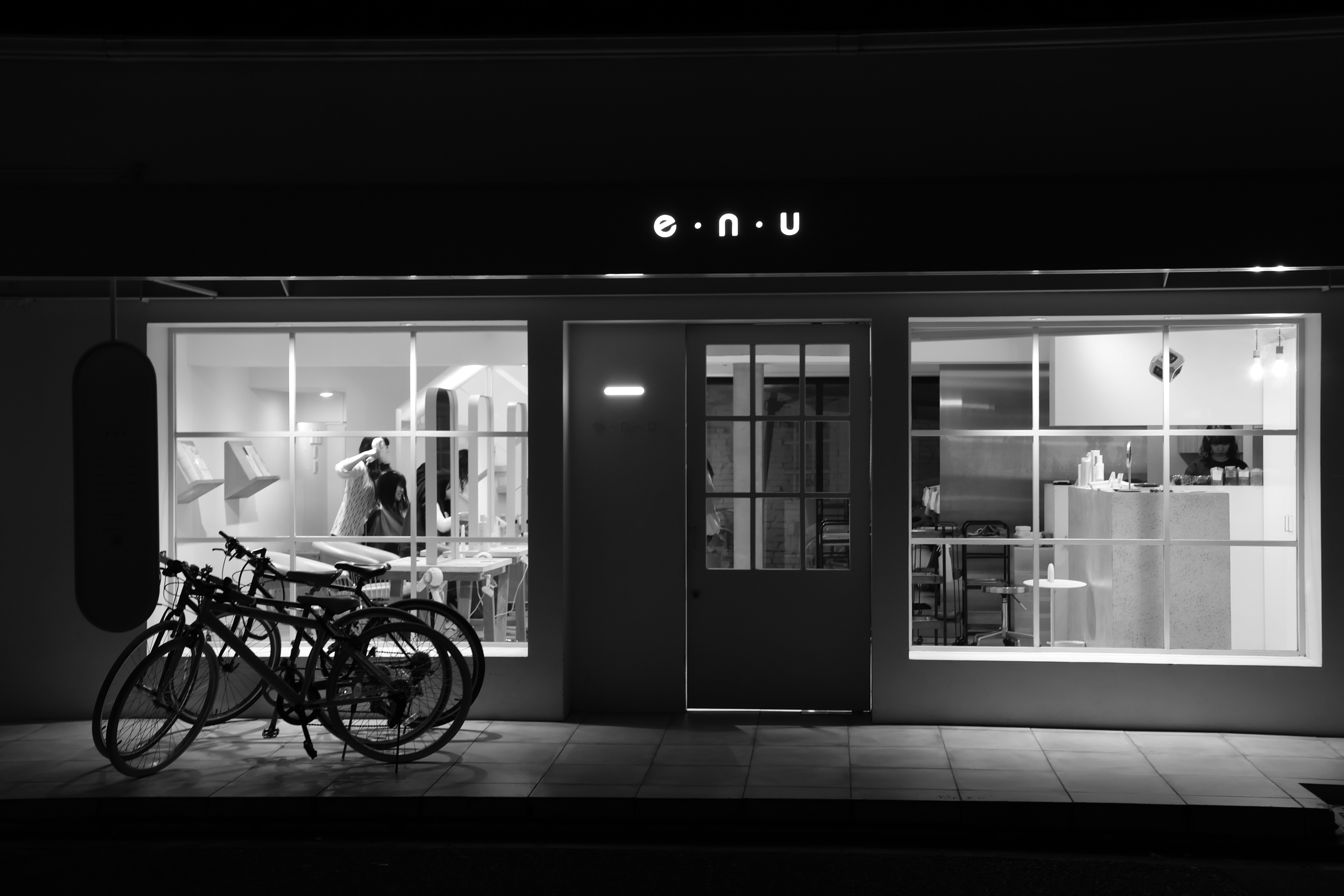 Storefront with bicycles parked in front at night.