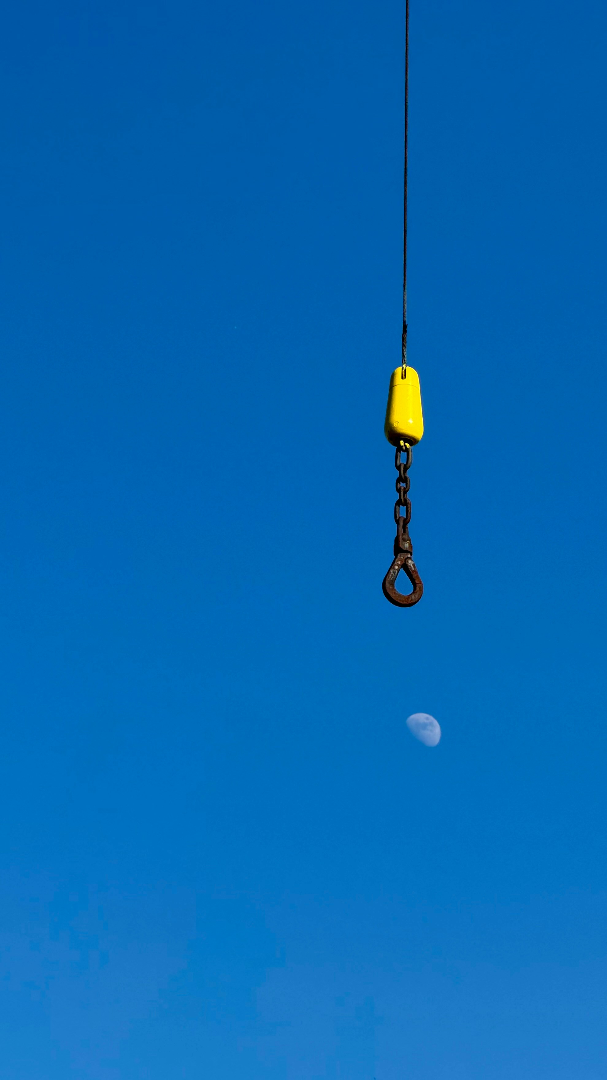 Yellow吊 suspended lure against a cobalt sky with the moon lingering below
