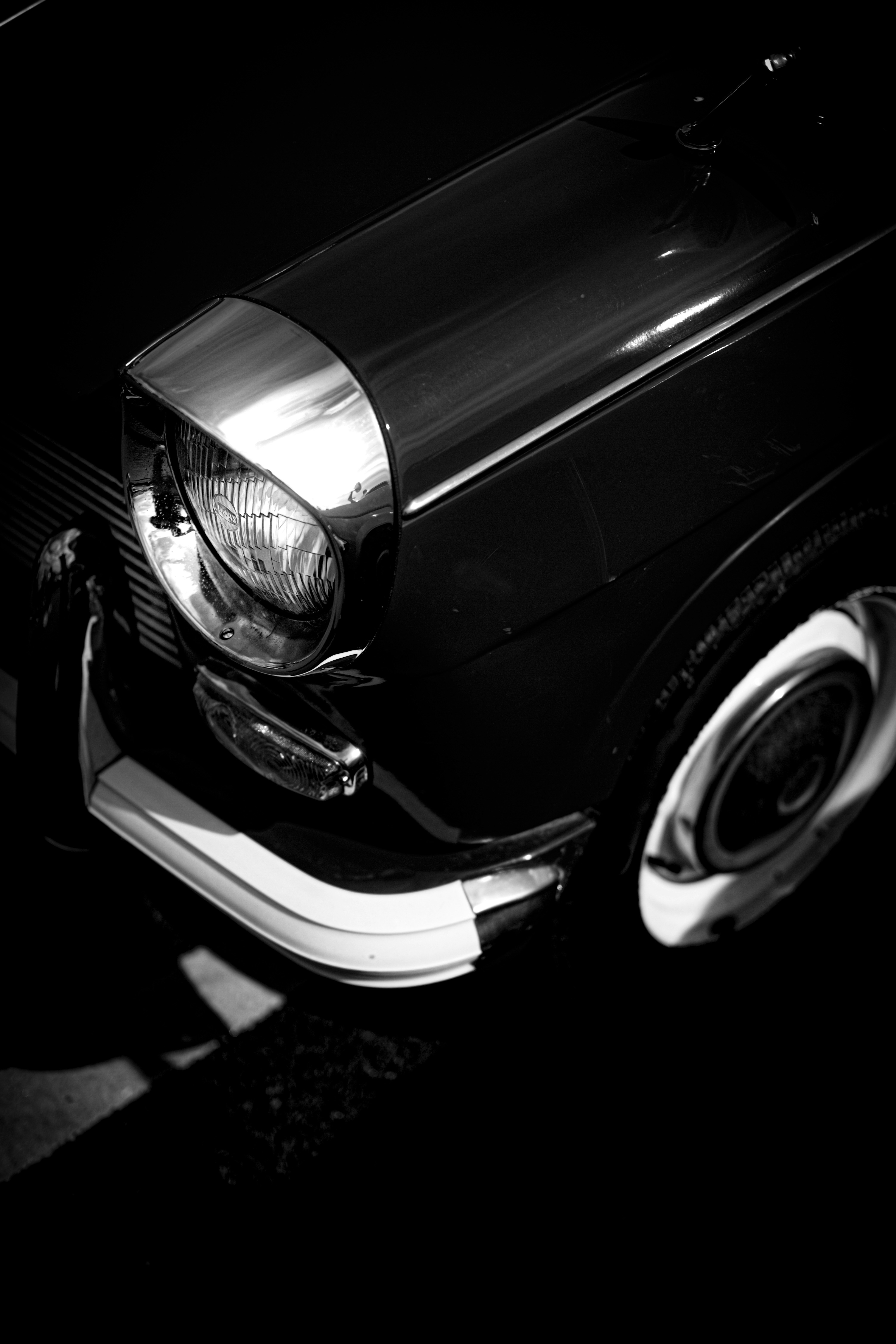Silent Chrome: A Vintage Car's Headlight Surfaces in Mono