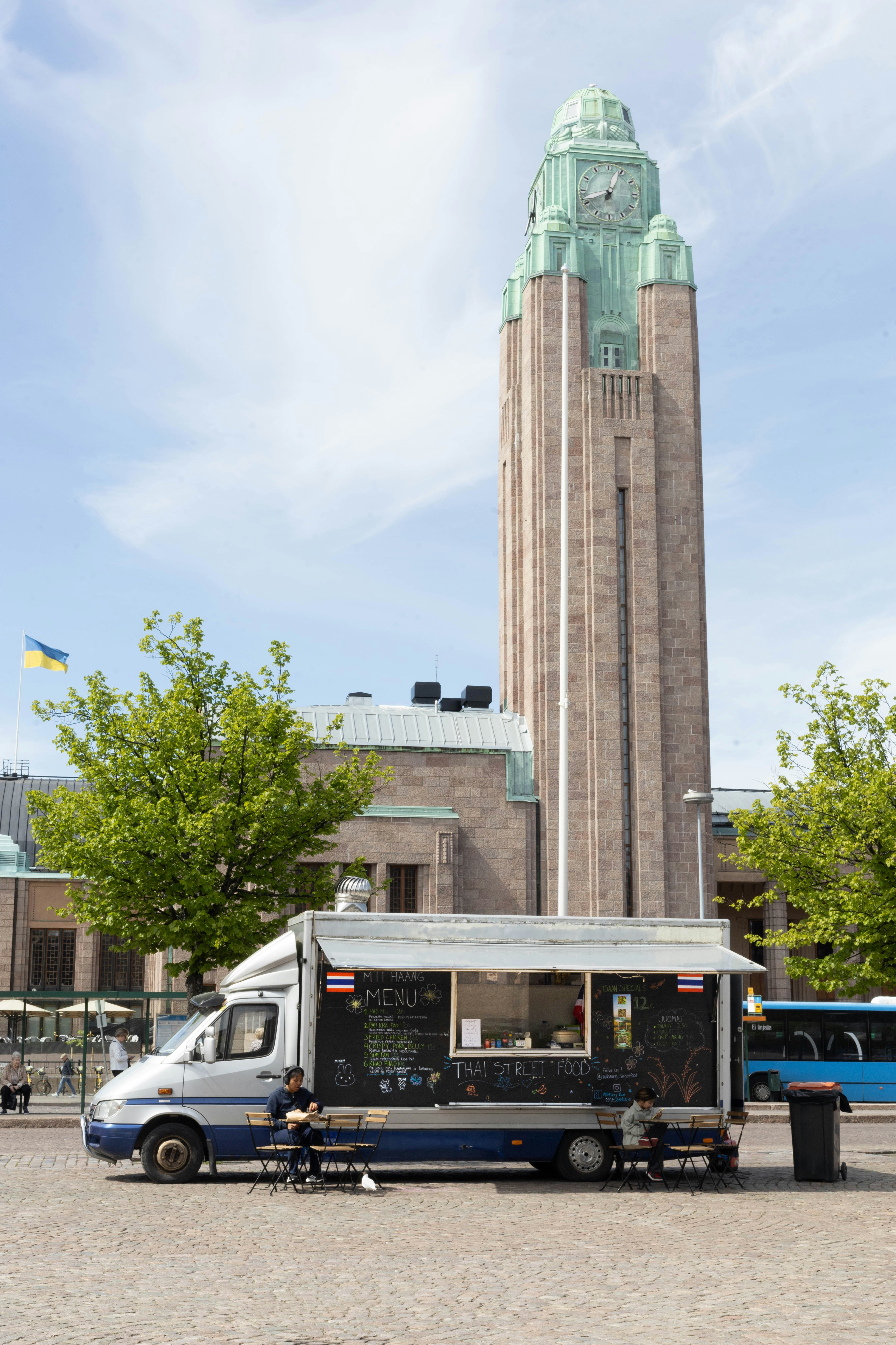 Food truck in a sunlit city square with a towering clock tower