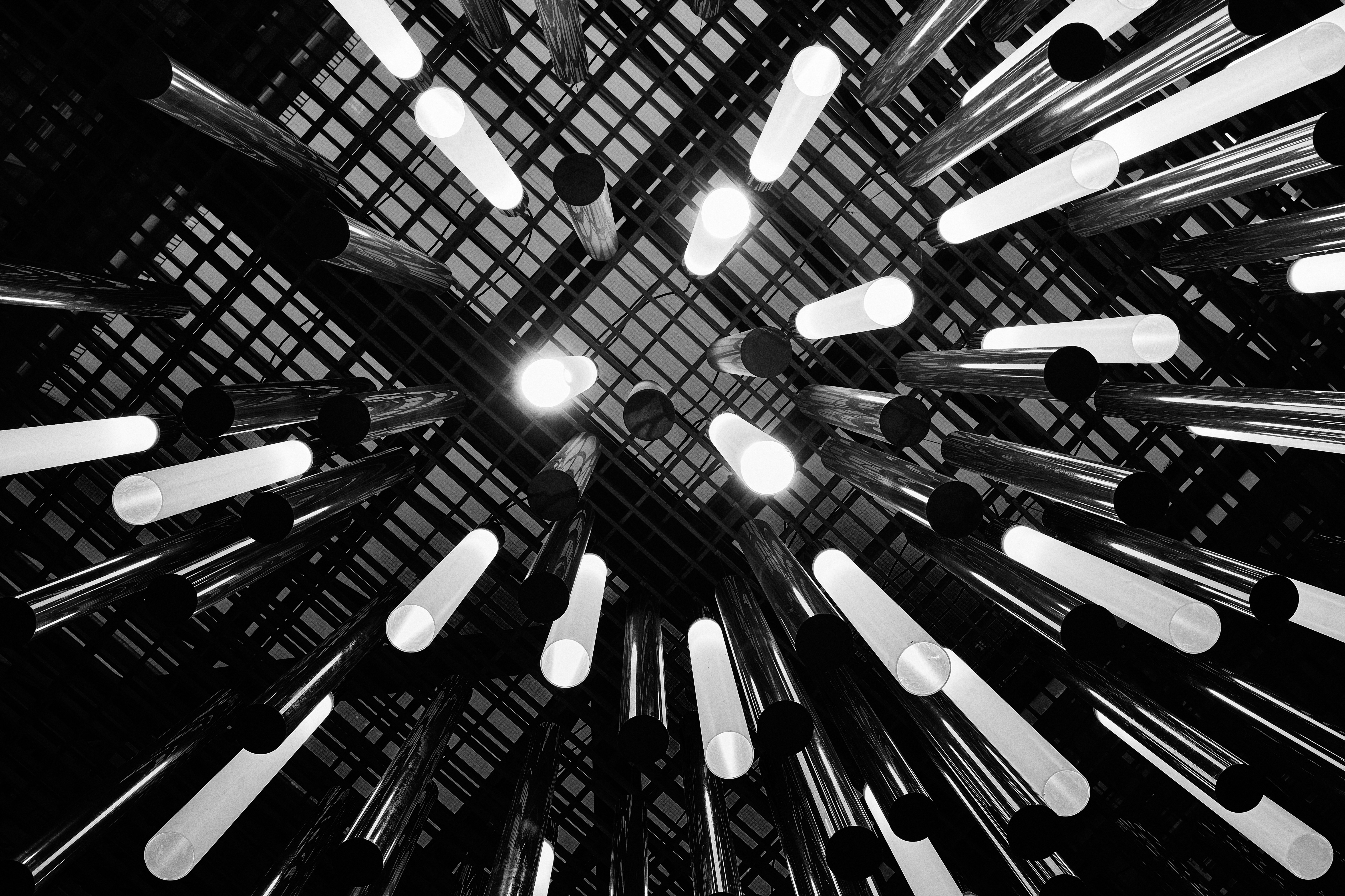 Abstract view of glowing cylindrical lights against a grid ceiling.